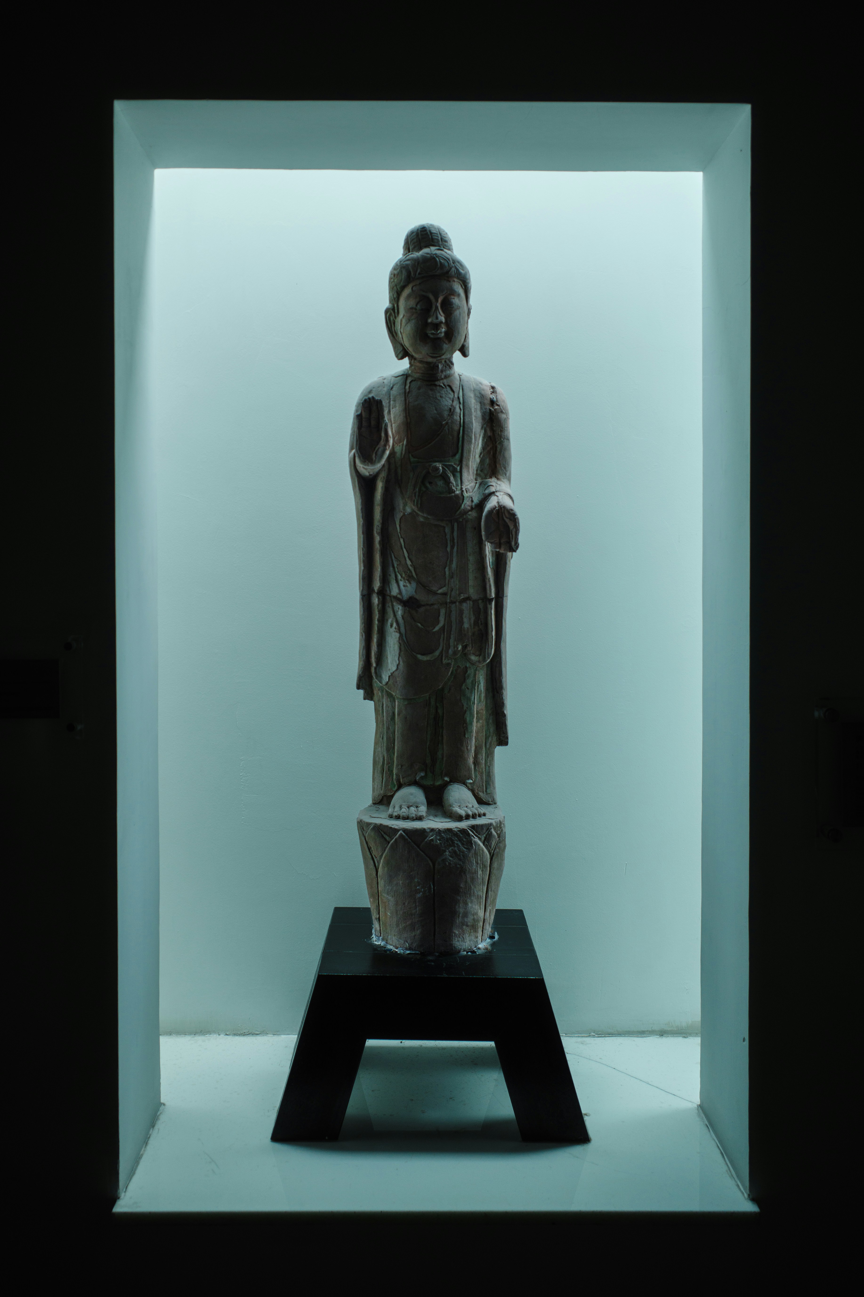Centered Gilt: A solitary Buddha statue in a luminous alcove