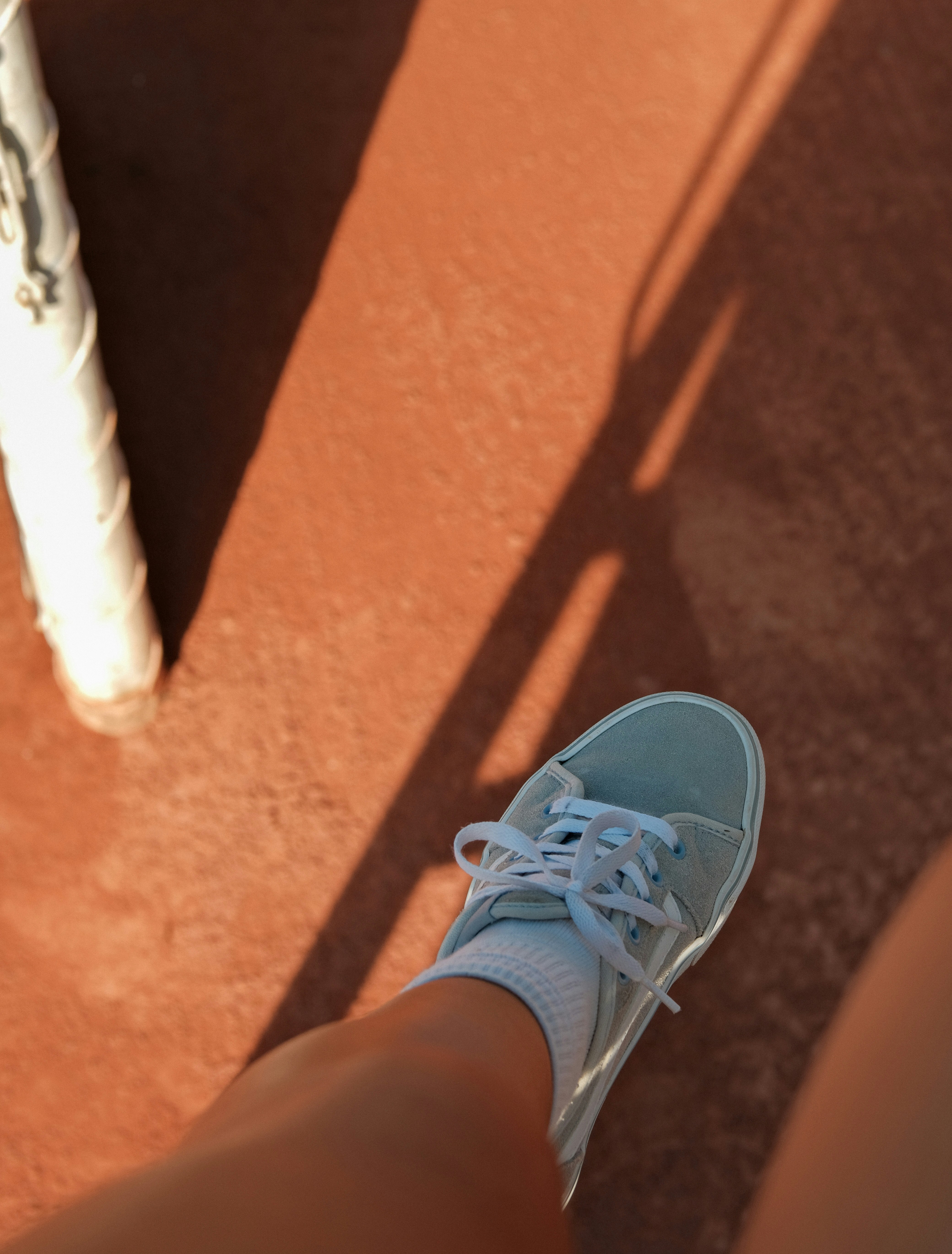 Stride in Shadowed Terrace: A Blue Sneaker Steps Into Warm Light