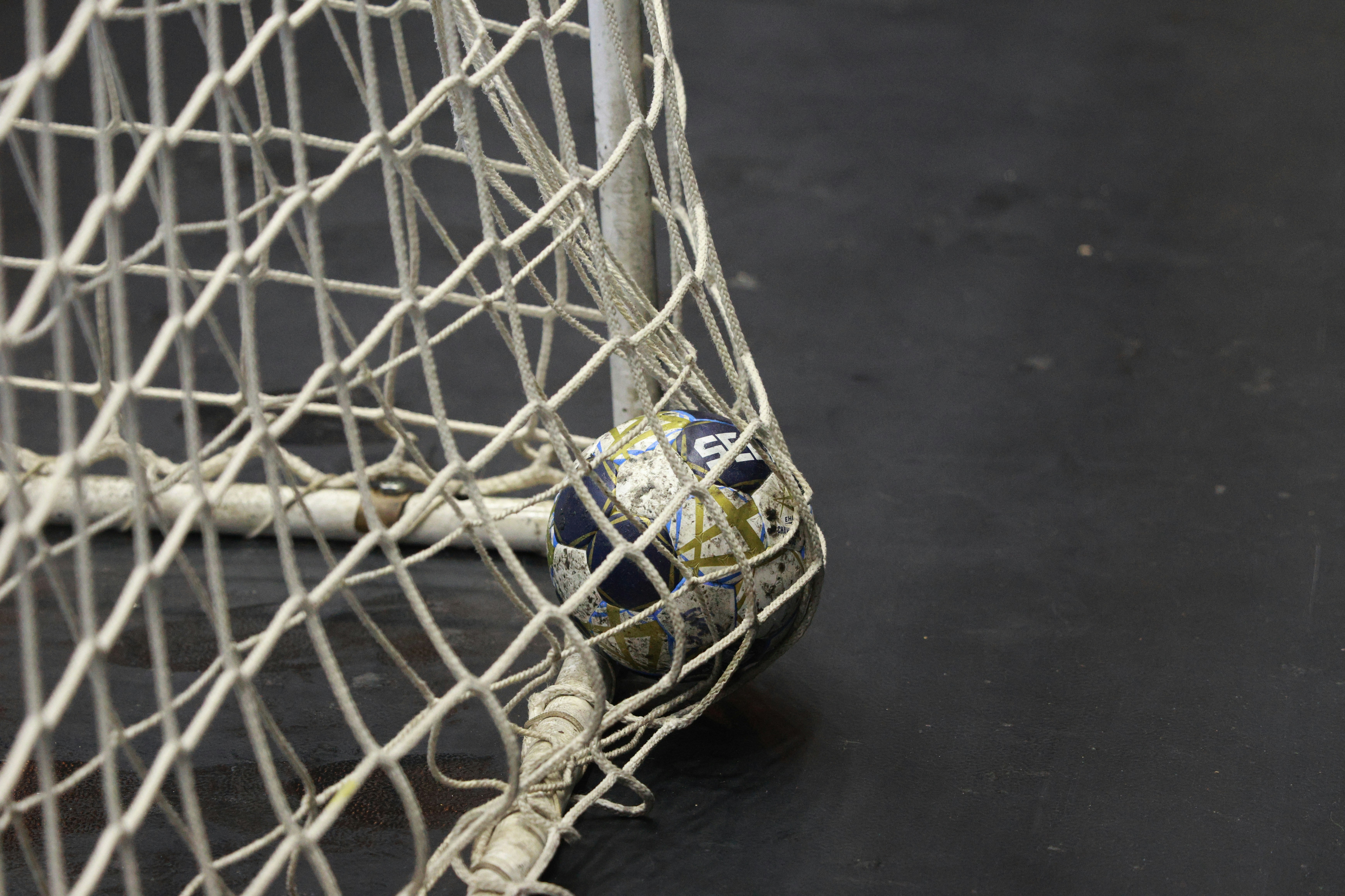 Tiny Target: A Weathered Soccer Ball Nestled in a Frayed Net