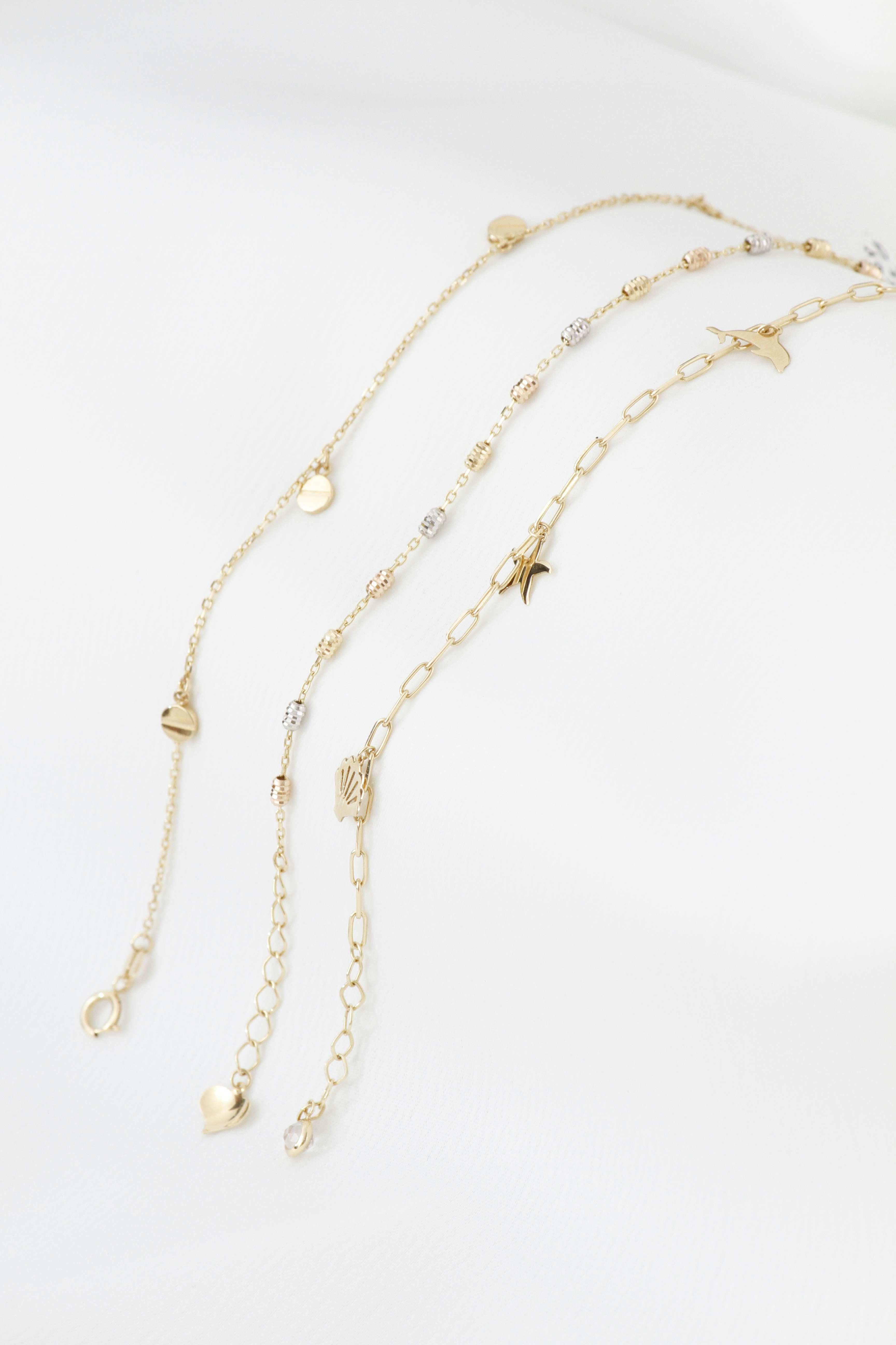 Delicate gold bracelets resting on a white satin backdrop
