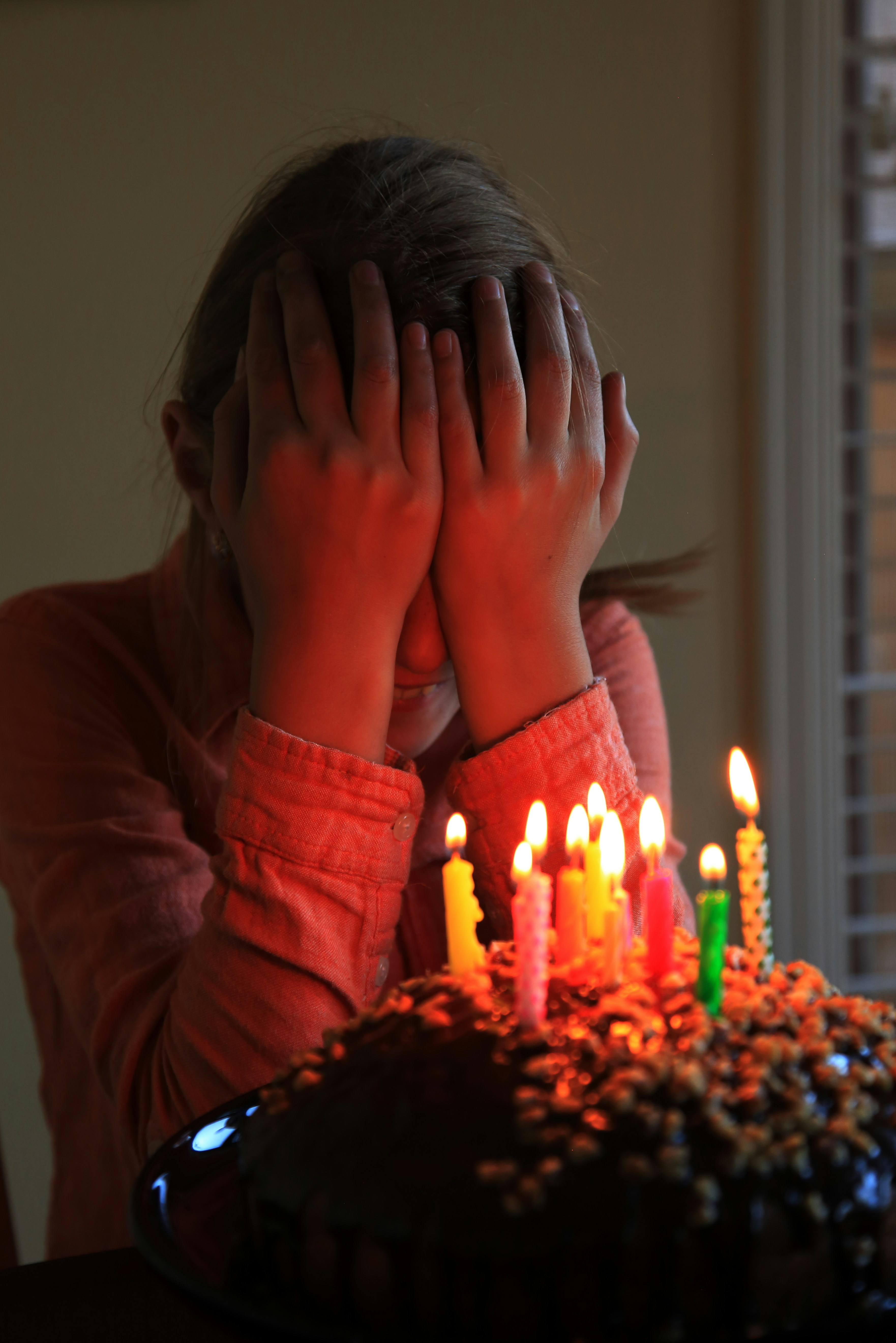 Candlelit Birthday Silence: A Child Hides Behind Hands