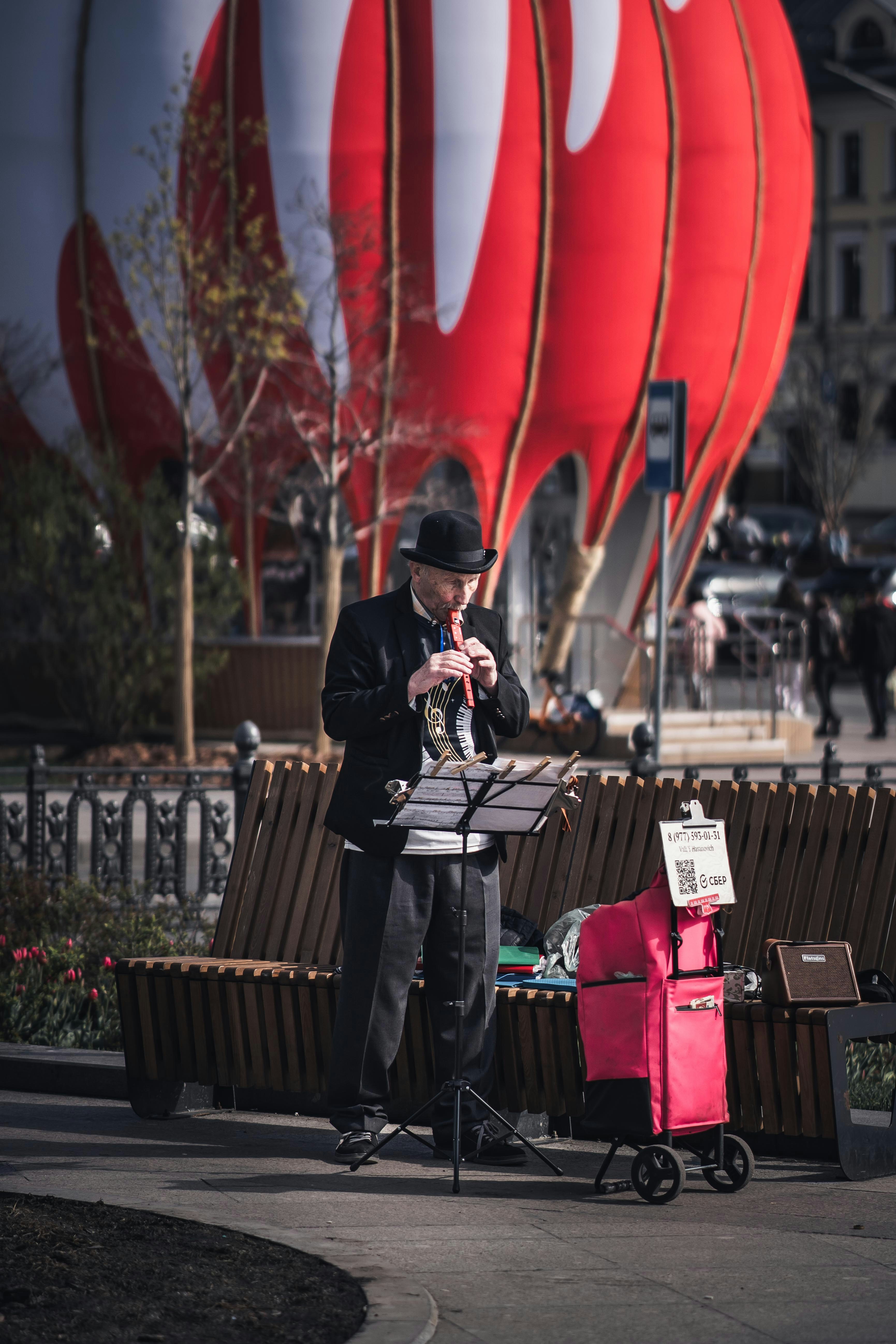 Street Sax: A Busker's Tune Beneath a Crimson Balloon Installation