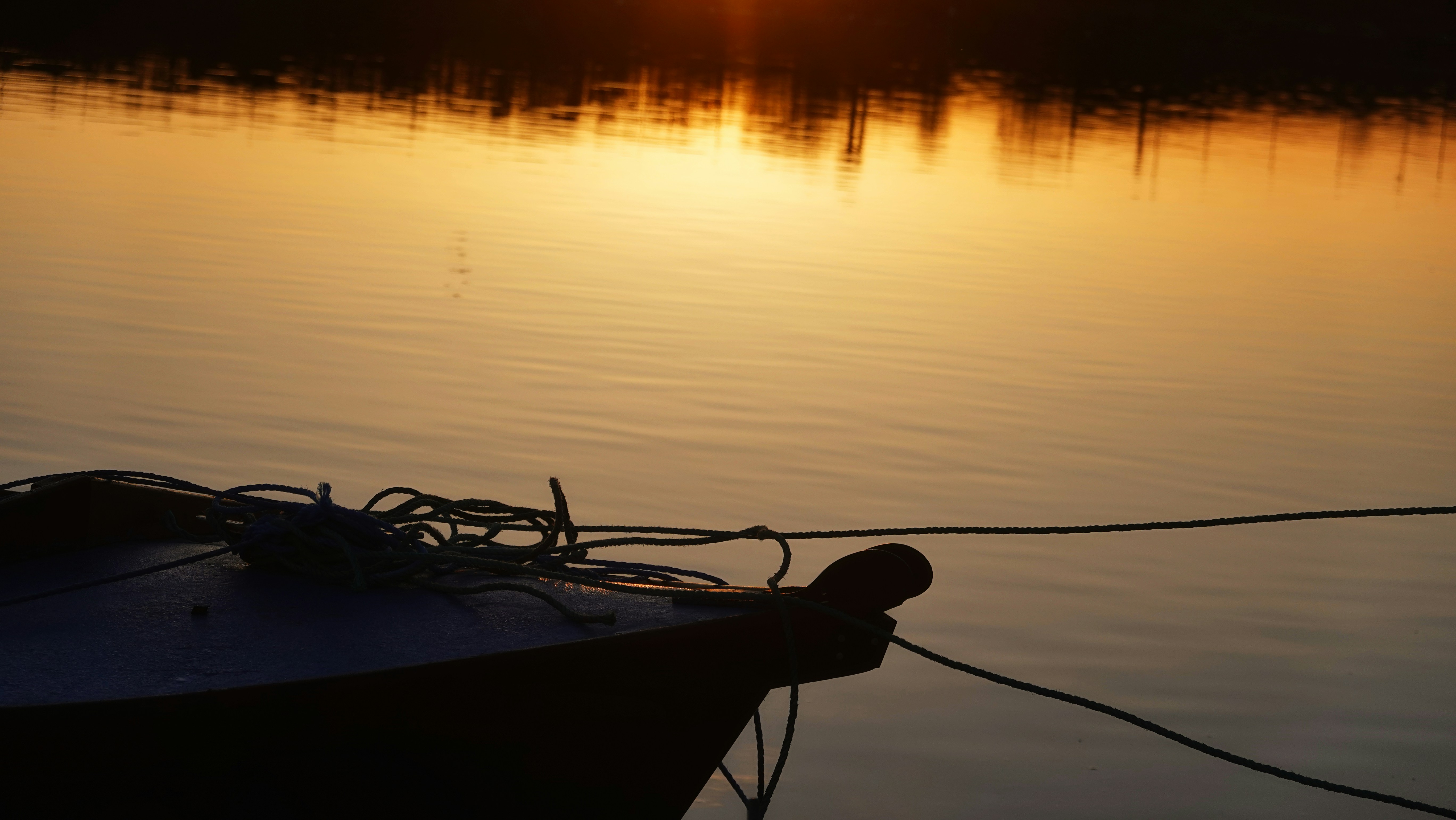 Silhouette at Dusk: A Quiet Tethered Boat on Glassy Water