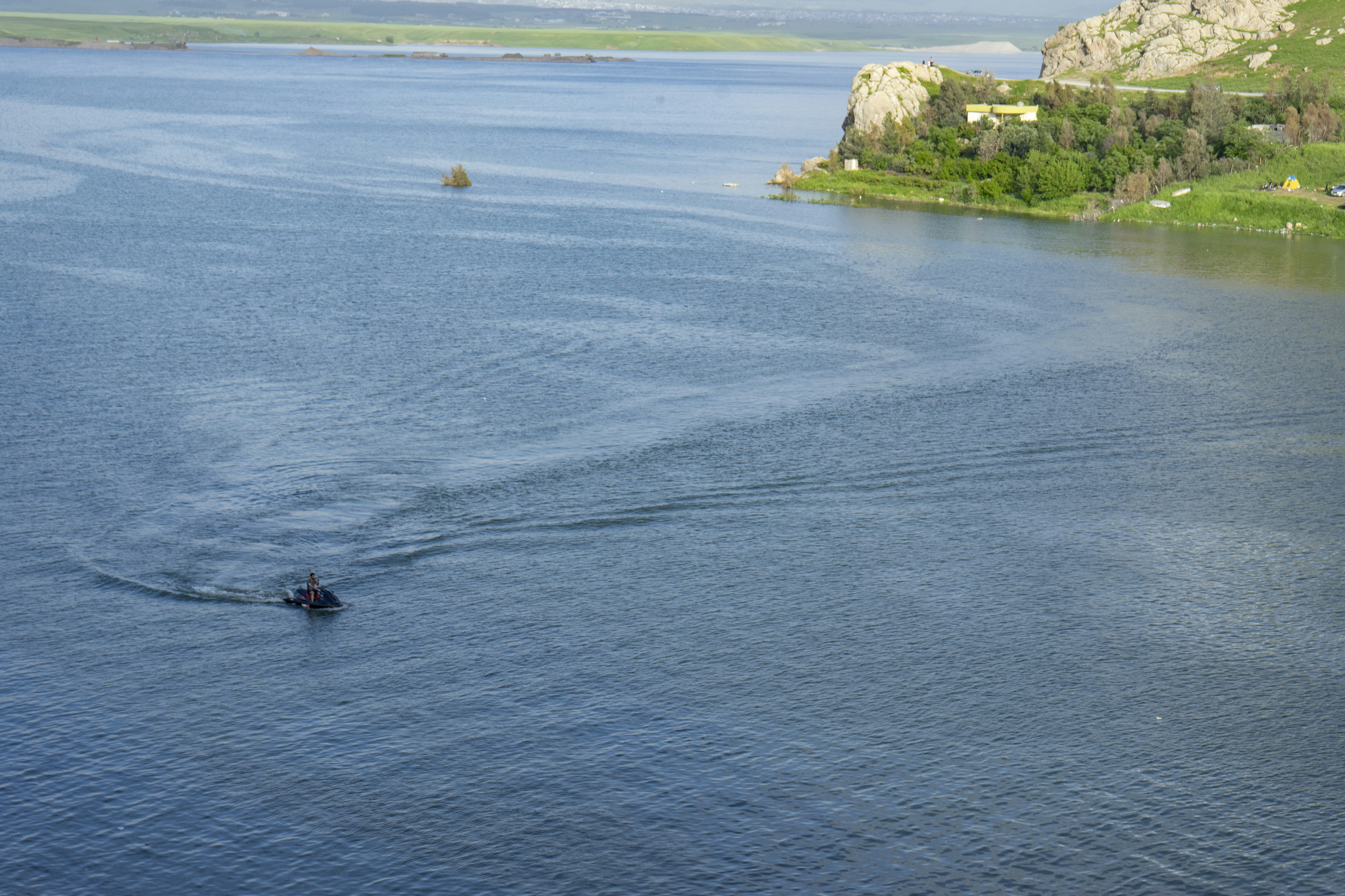 Vessel Tracing a Wake Across a Quiet River Curve