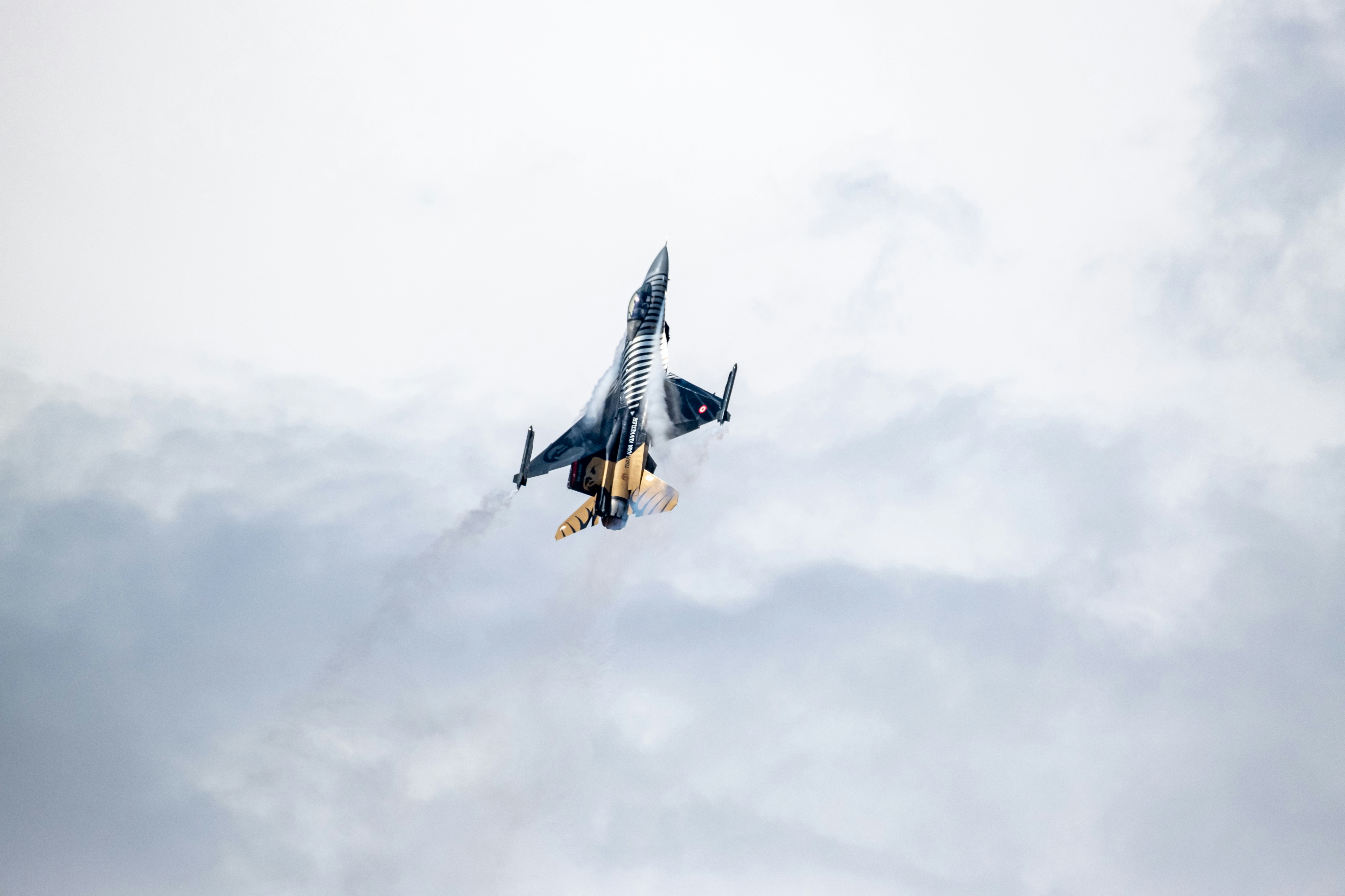Jet-powered ascent: a lone aircraft carving through pale clouds