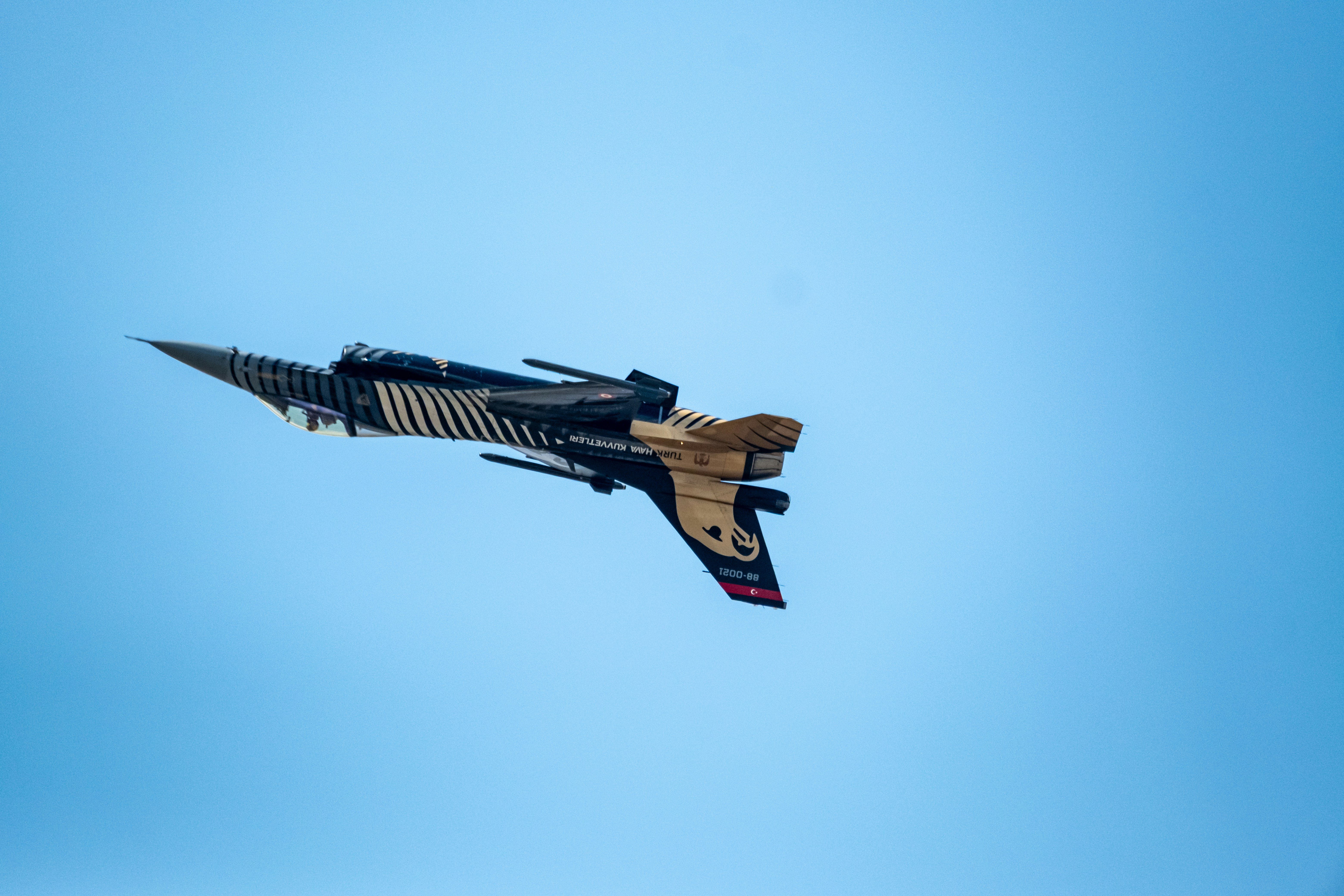 Jet silhouette slicing through a clear blue sky