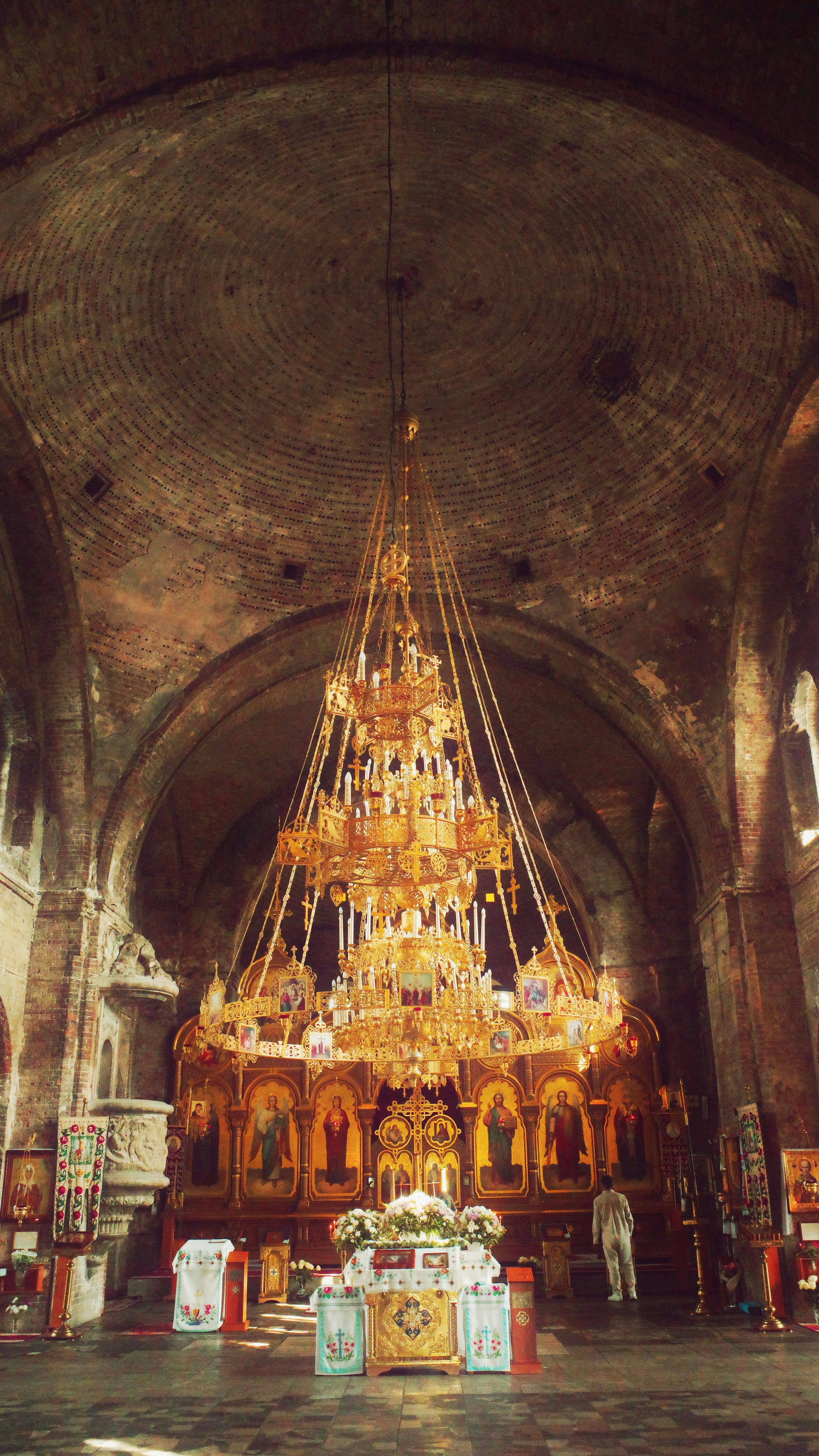 Golden chandelier above an ornate altar inside a stone church