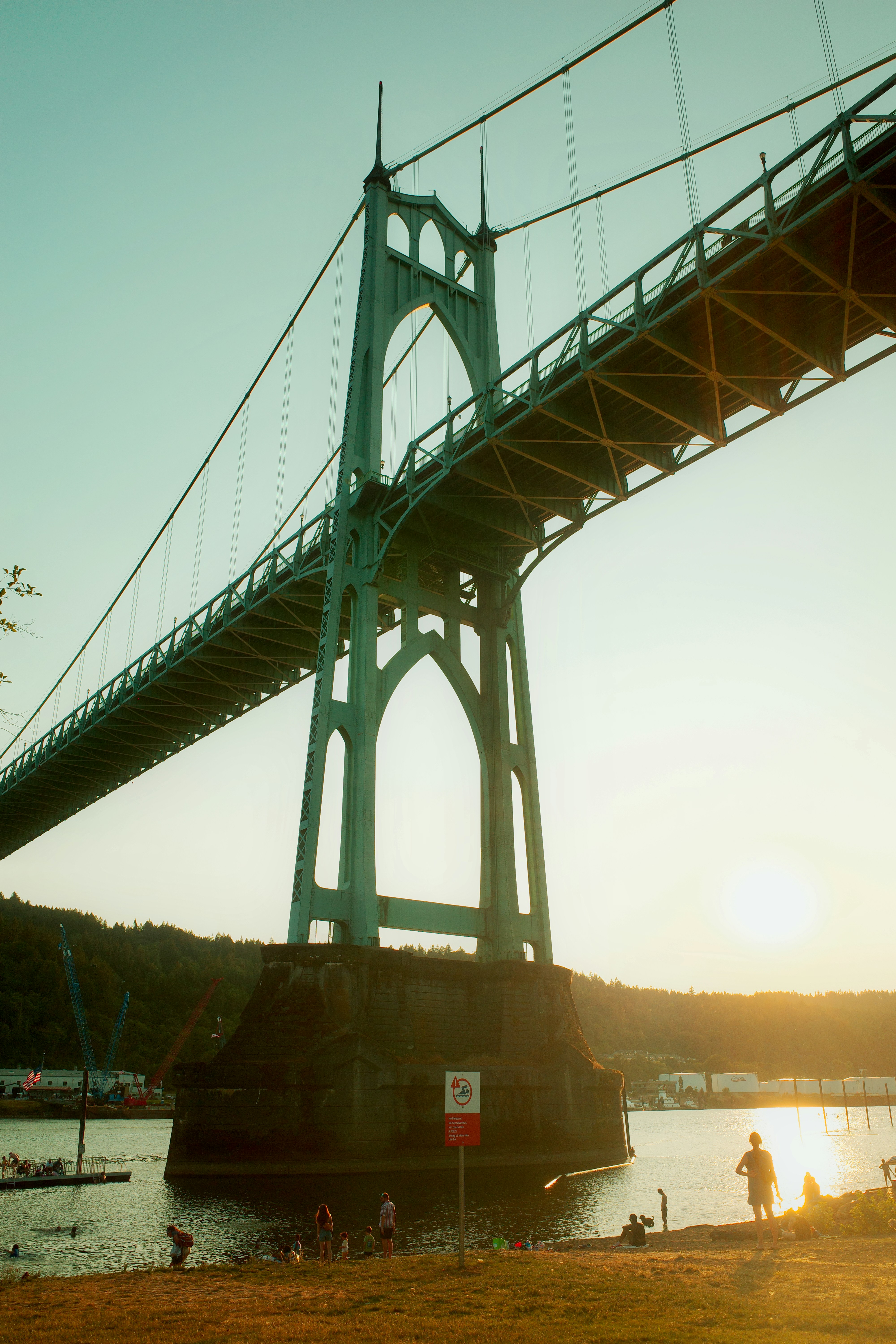 Golden Hour Span: The Mighty Suspension Bridge Framed by a Riverside Crowd