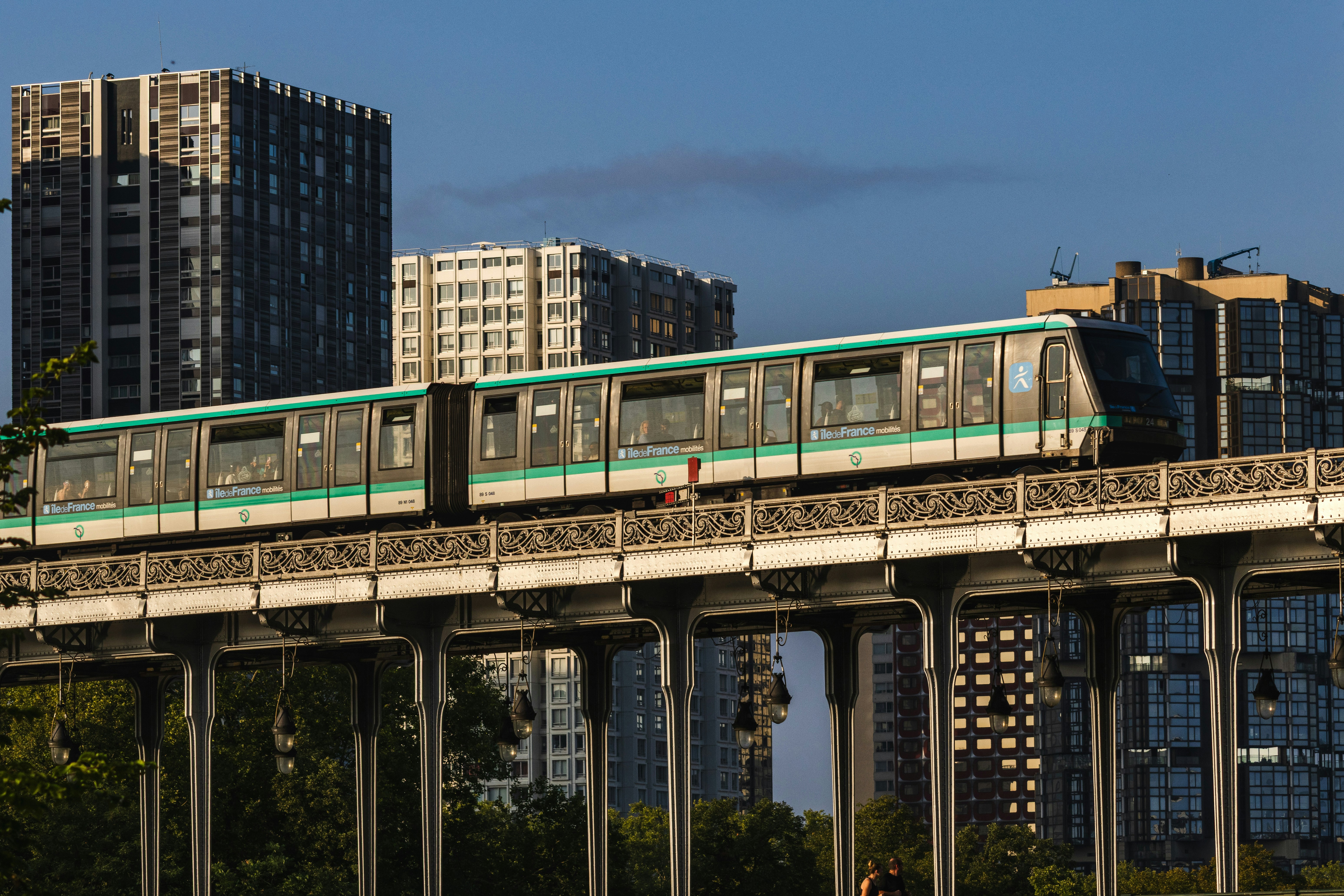 Green stripe metro glides over iron arches above the city