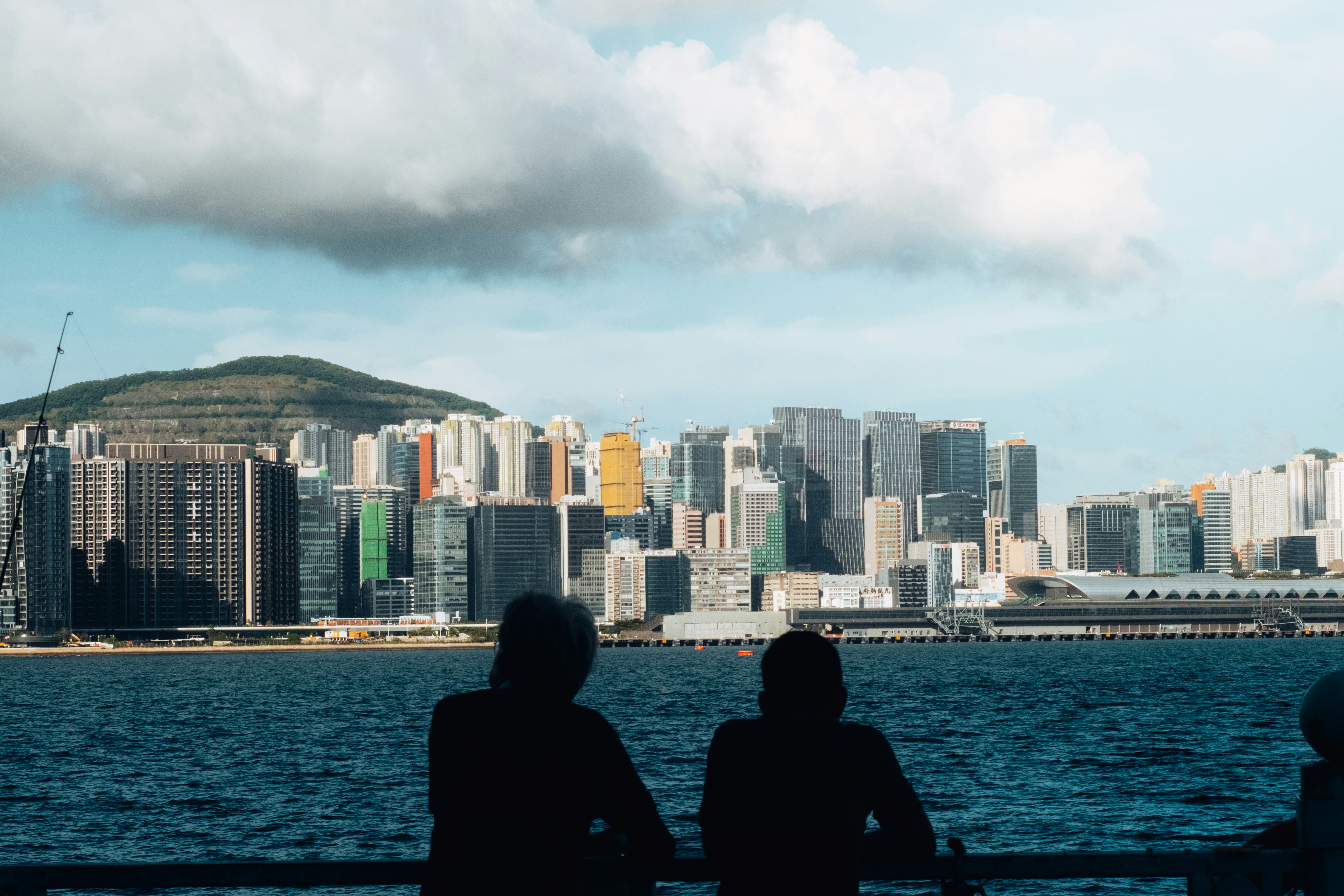 Two Silhouettes against a City Skyline by the Waterfront
