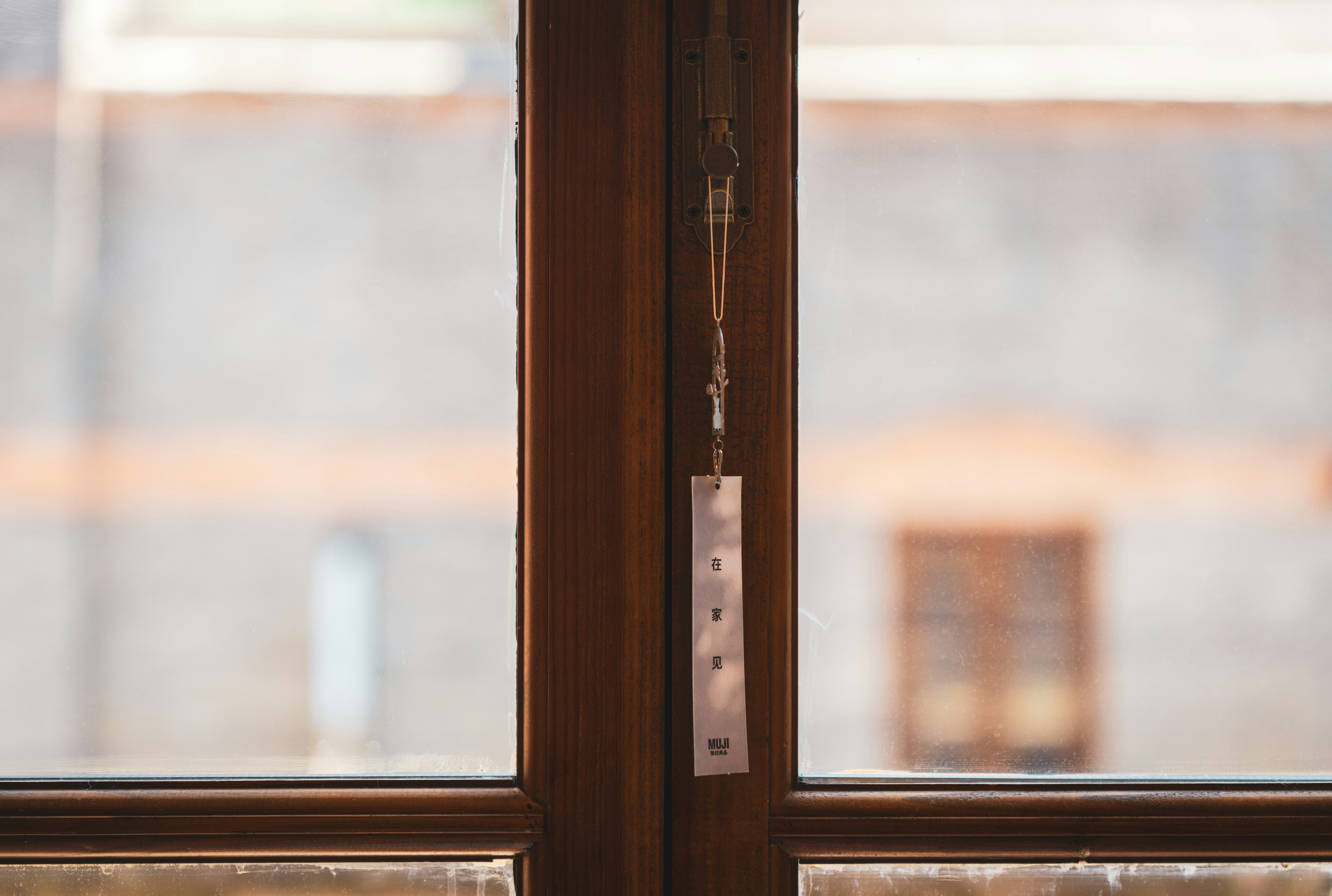 Between Panes: A Vertical Charm Dangles at a Café Window