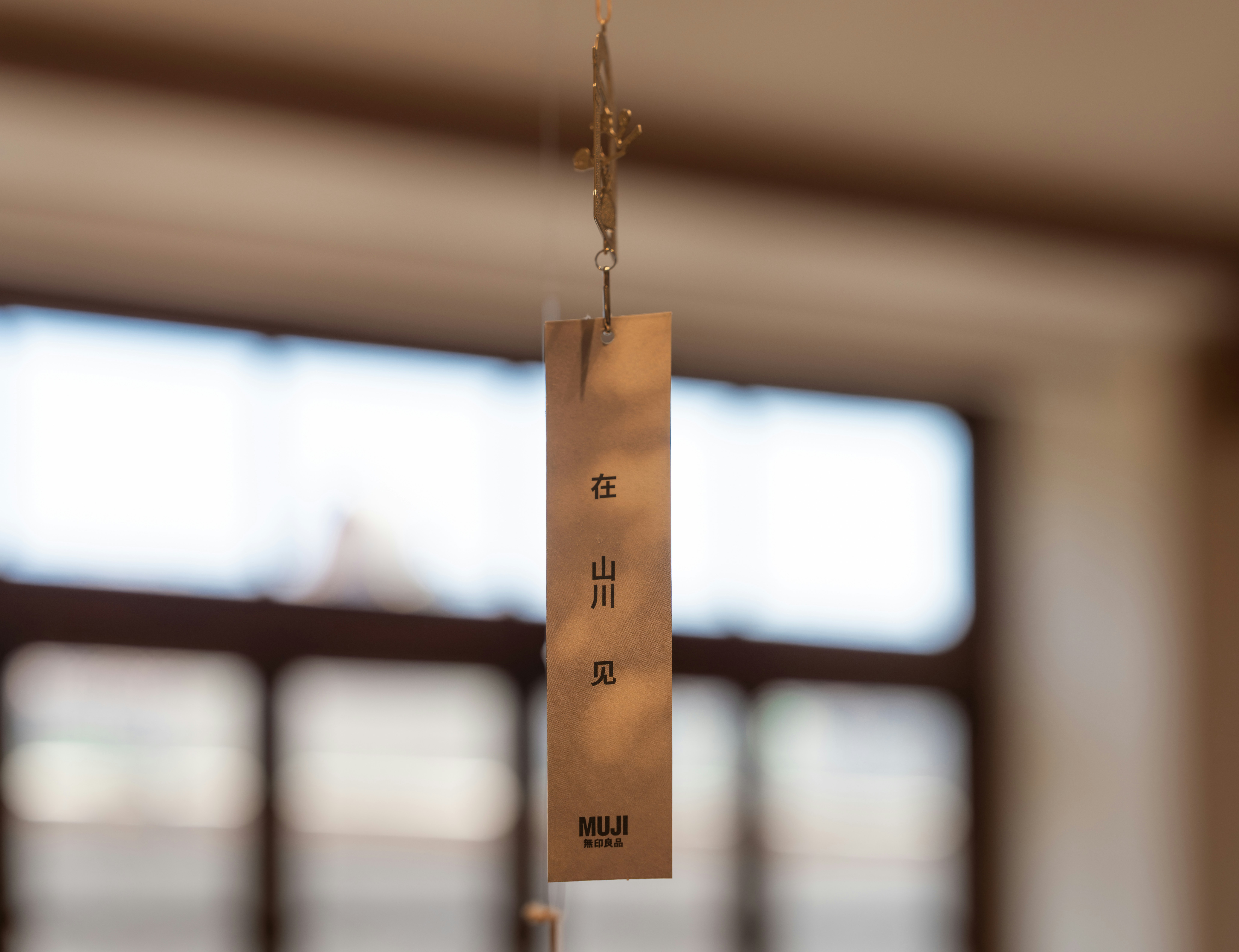 Wind-hung tag and soft-lit window: a quiet moment in a Japanese-inspired space