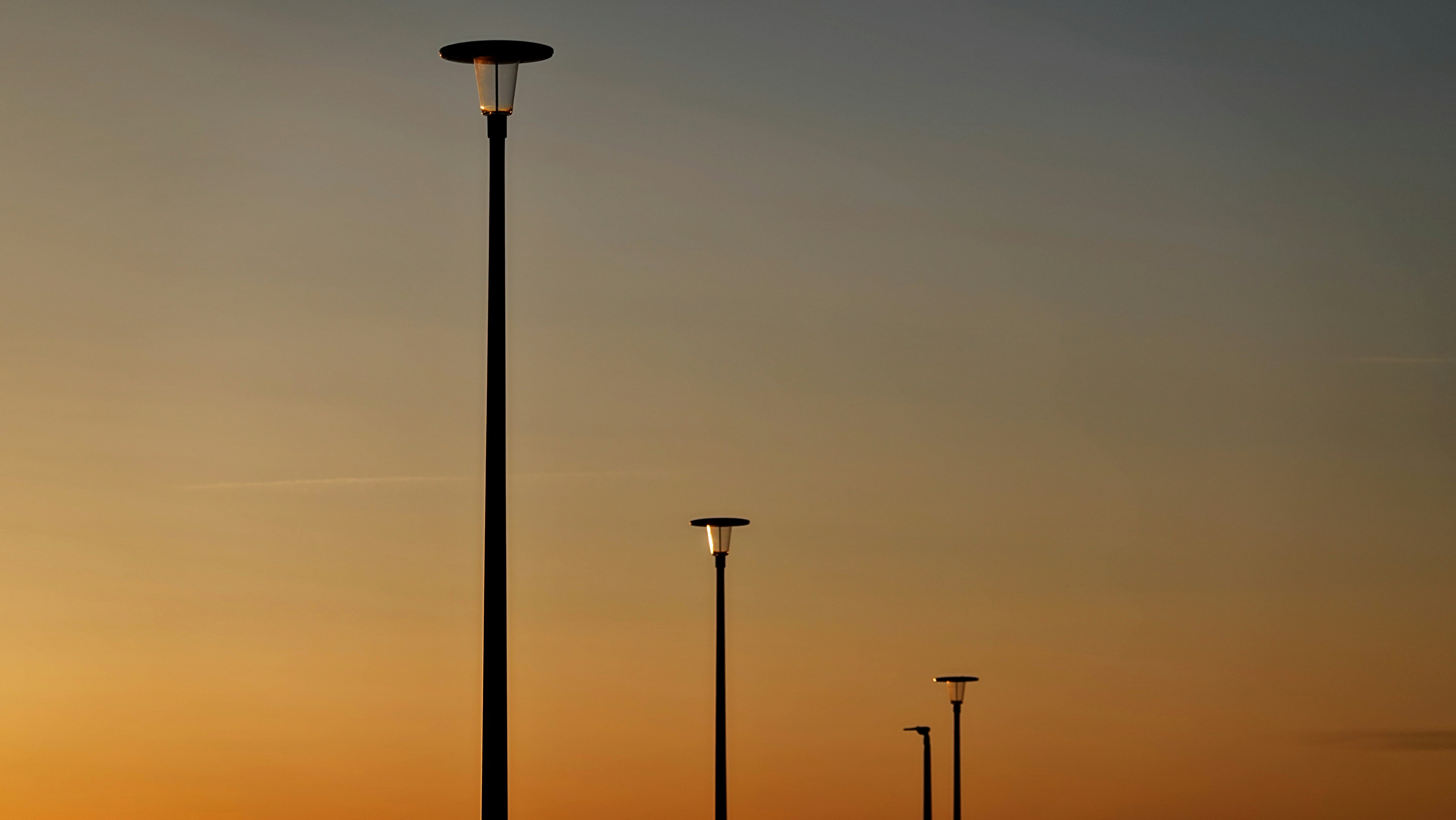 Pole Lights at Dusk: A Row of Street Lamps Silhouetted Against a Golden Sky
