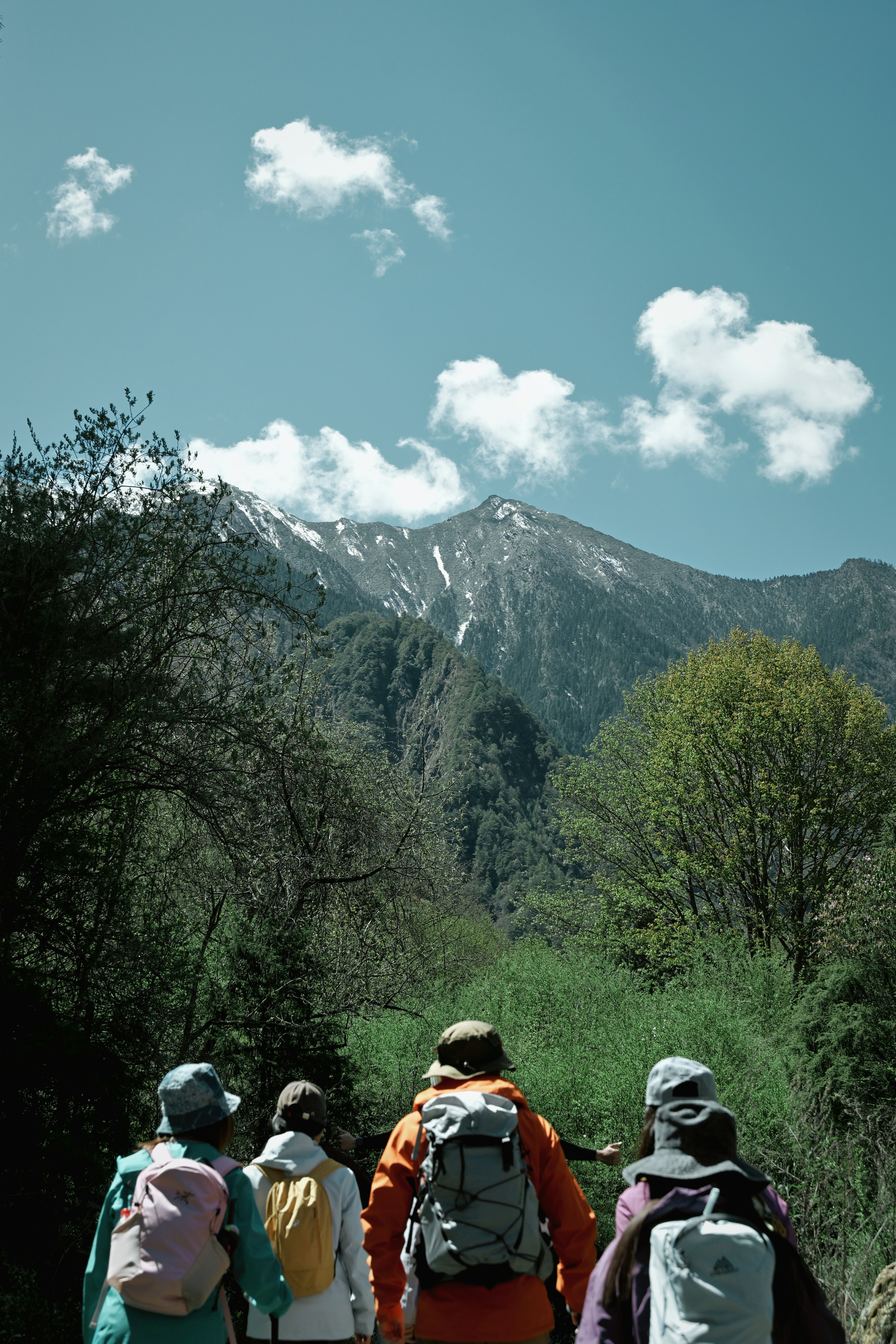 Hikers Descend a Mountain Path Under Expansive Sky