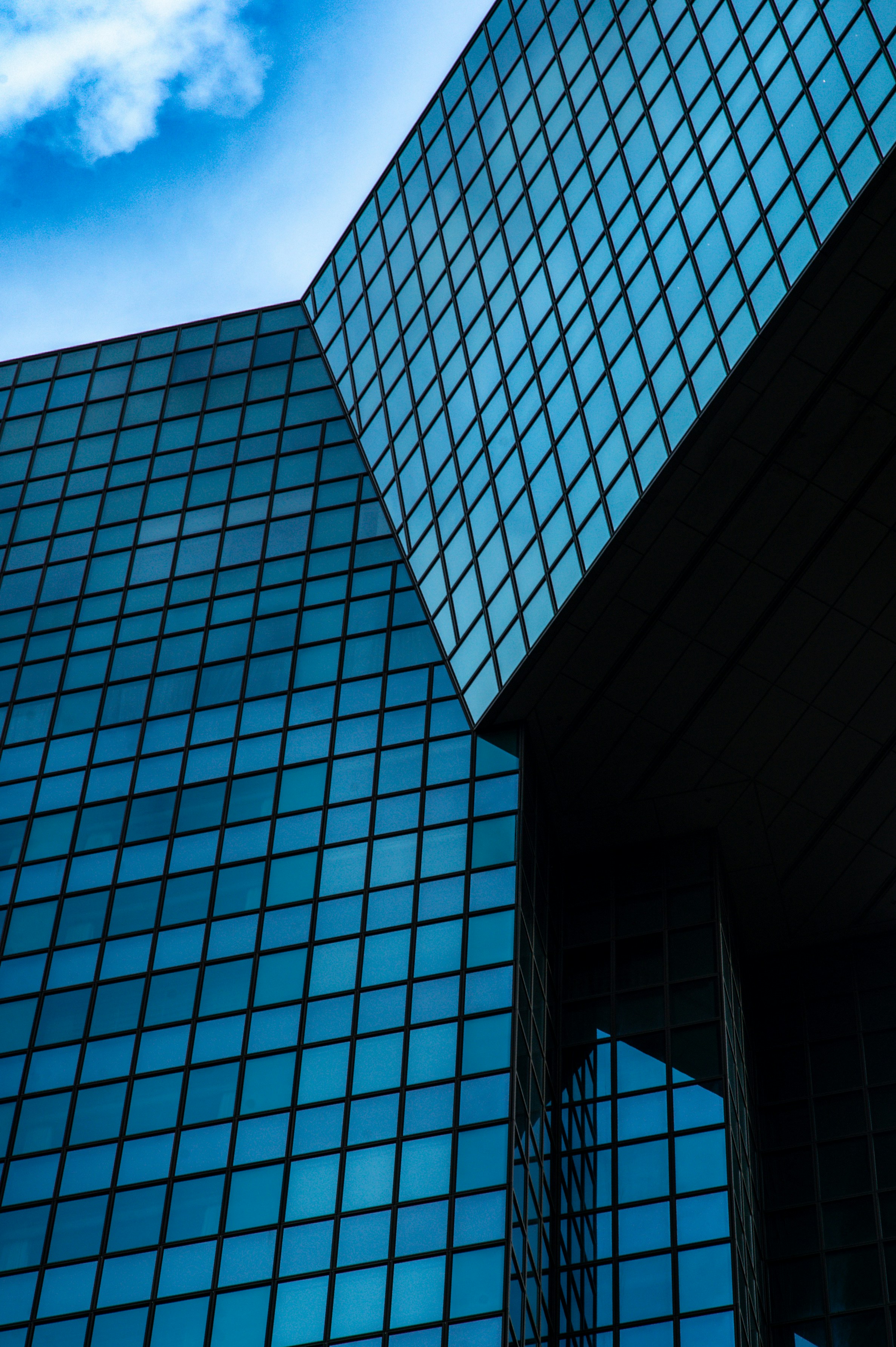 Glazed Angles: A Skyward Facade Converges into Shadowed Archways