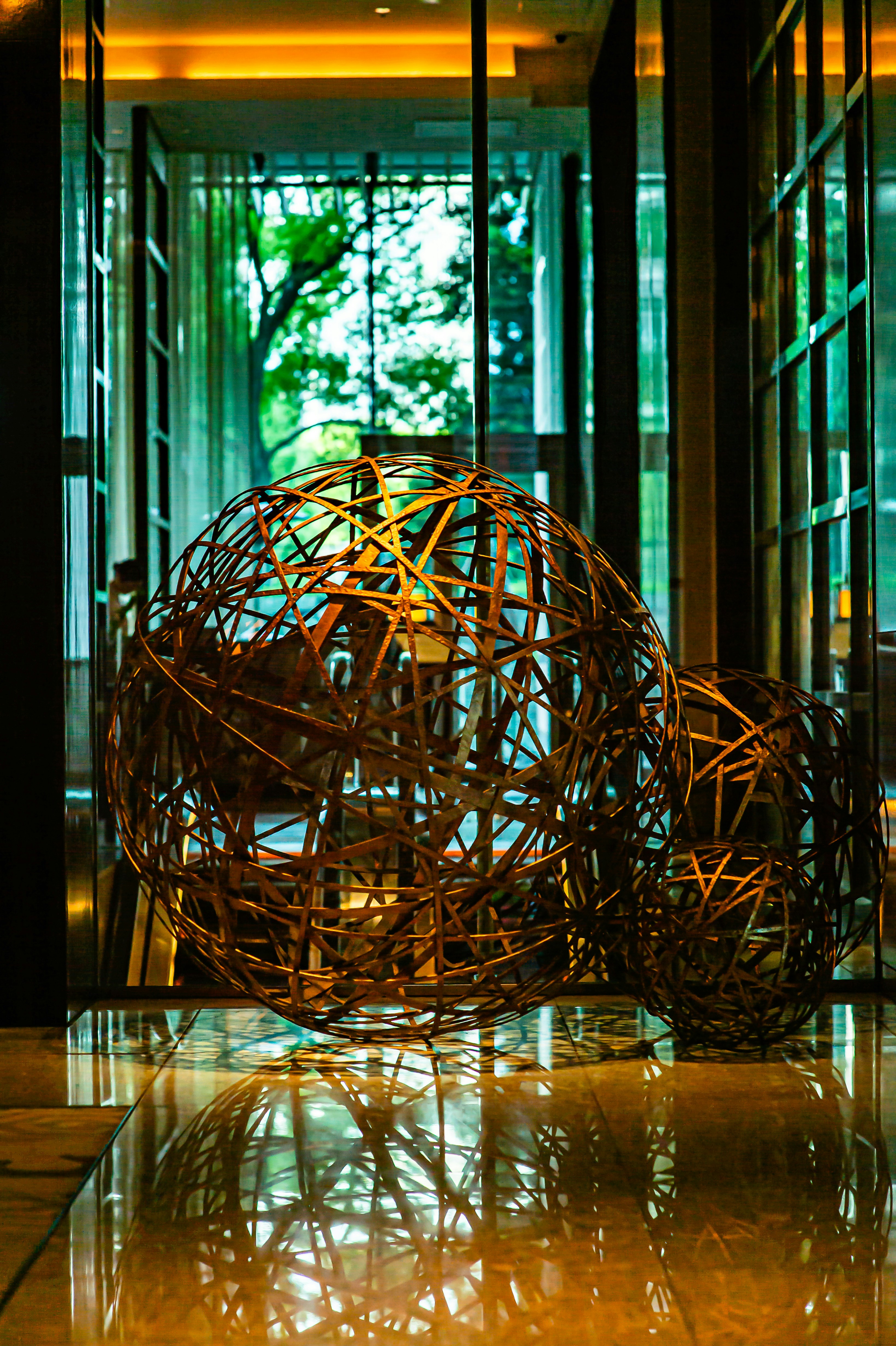 Sculpted Orbs in Glasshall: Metallic Meshes Echoing Light