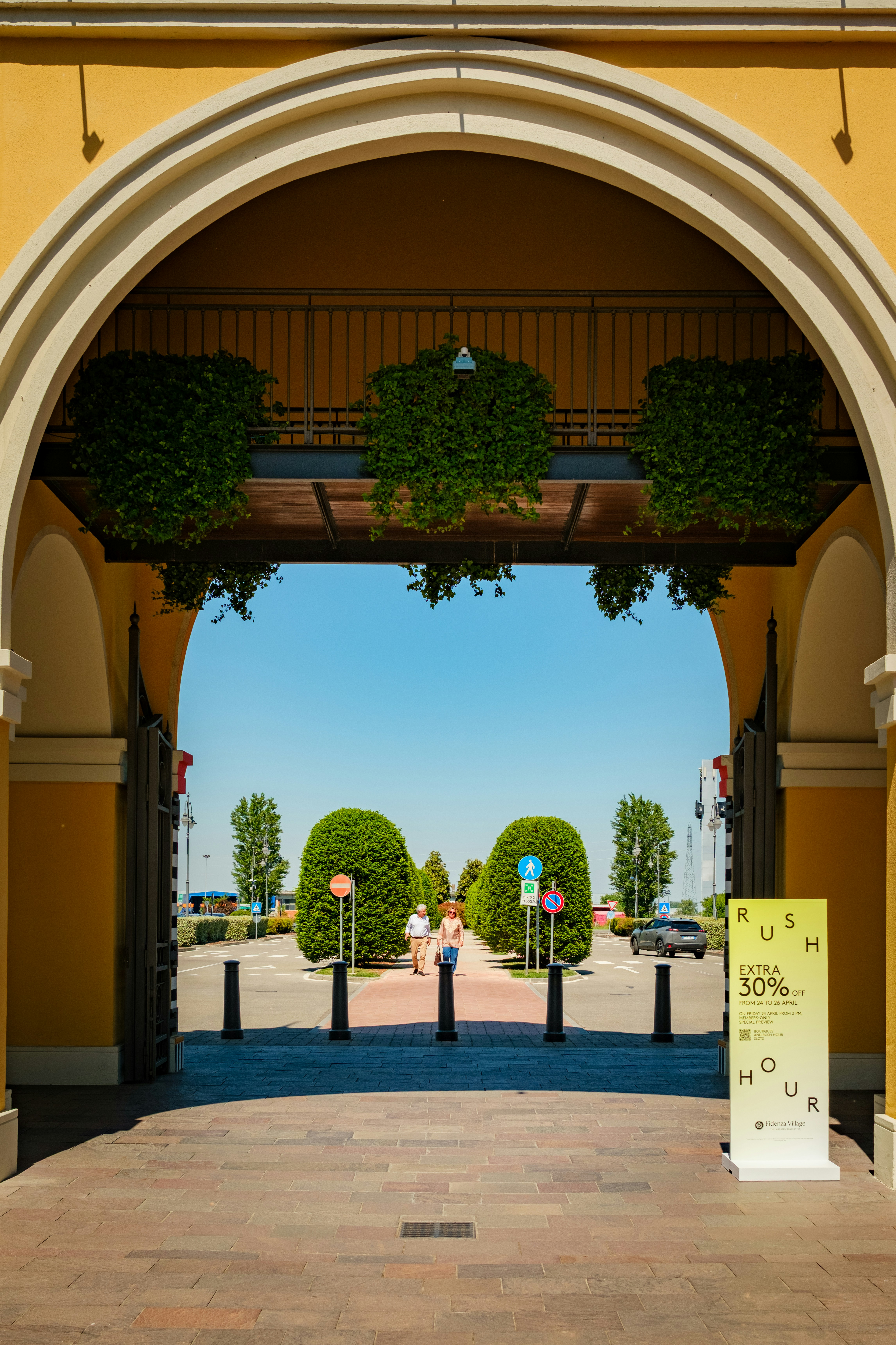 Courtyard Gateway: Sunlit Arch Framing People Beyond the Plaza