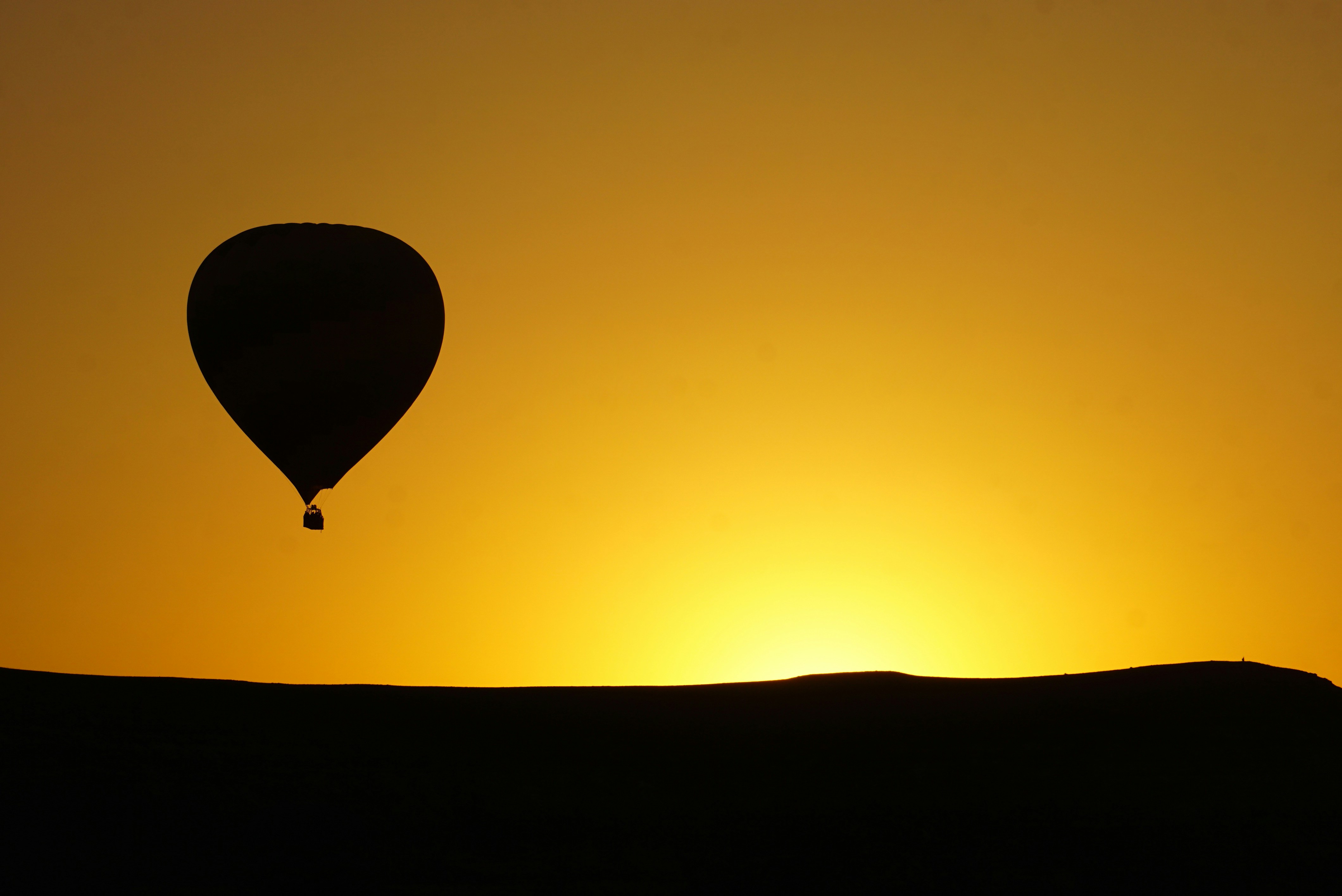 Balloon Spiral: A Lone Silhouette Against a Golden Descent