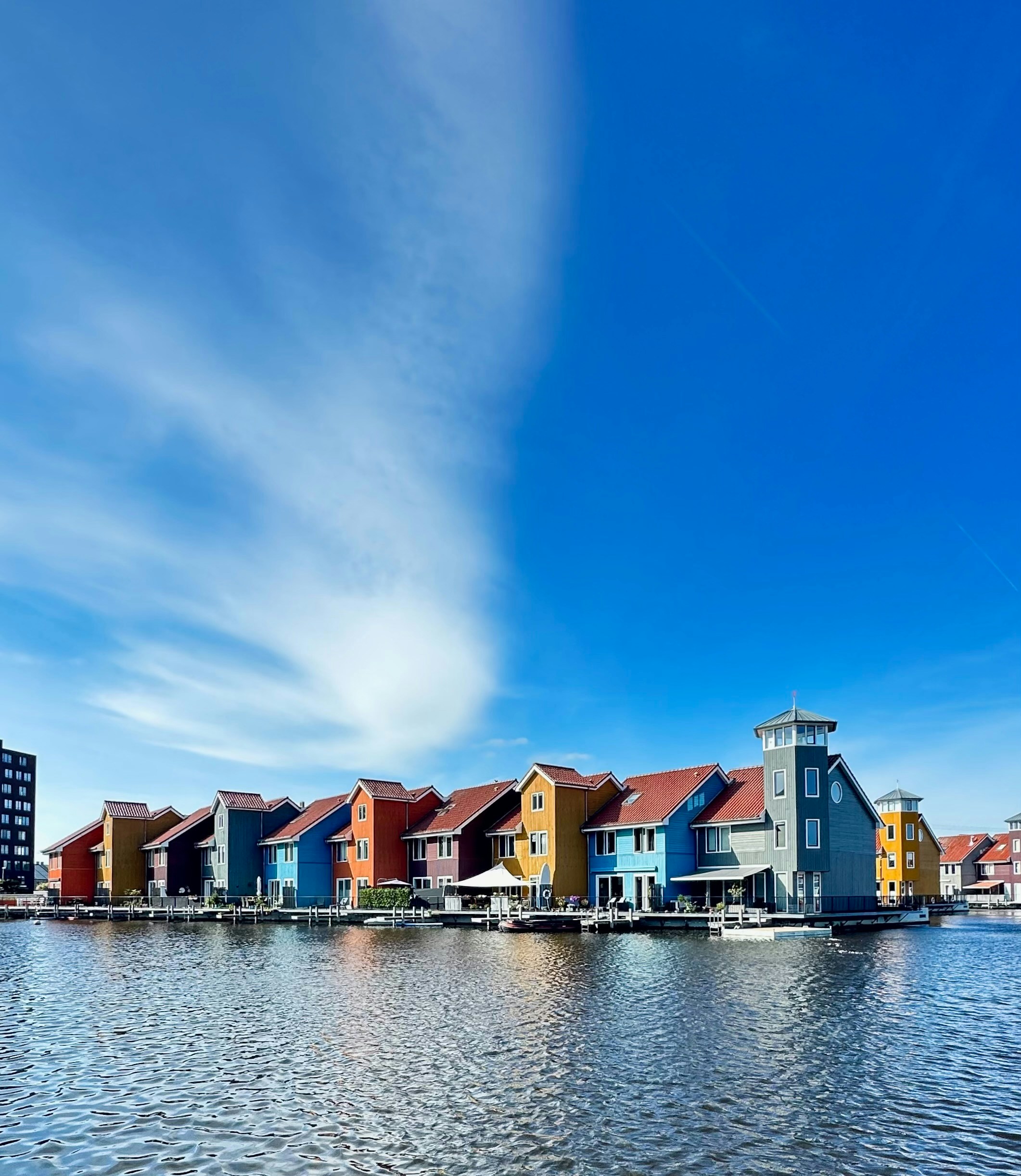 Colorful waterfront houses mirror a quiet harbor at midday