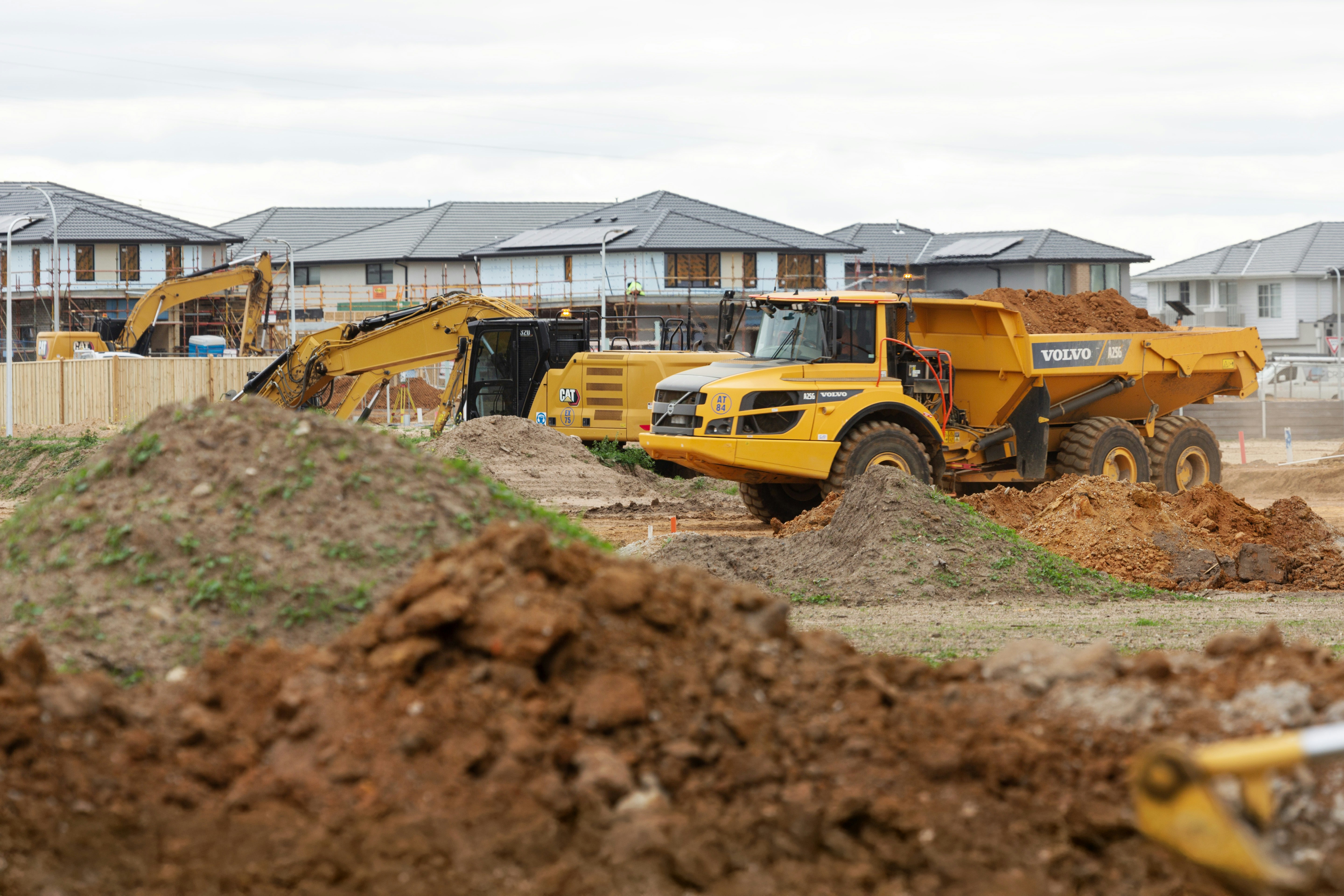 Yellow Dump Truck Amid Freshly Dug Foundation at Suburban Construction Site