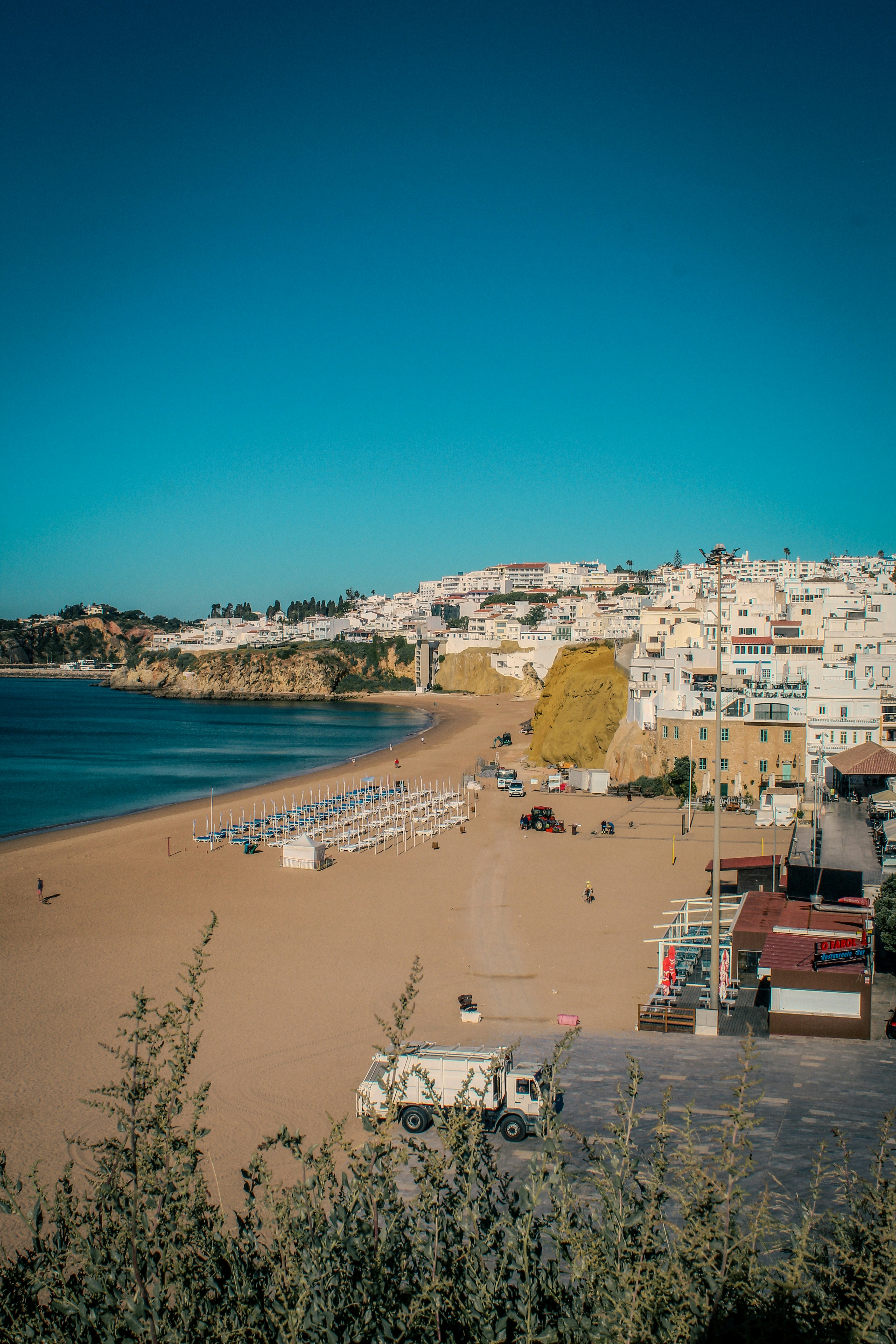 Sunlit Strand and Cliffside Village Beneath a Clear Blue Sky