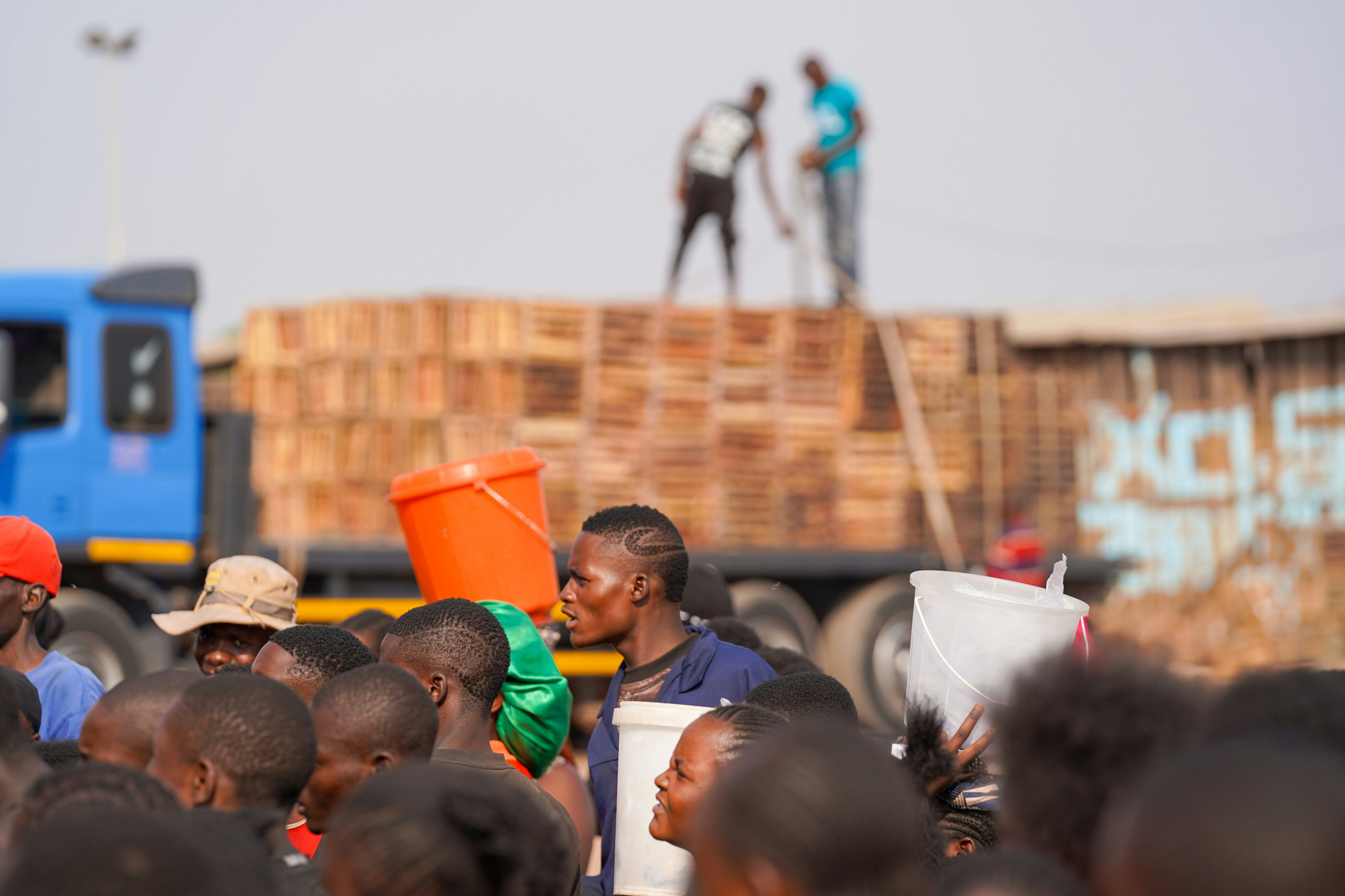 Queue of Hands and Buckets: A Busy Street Moment