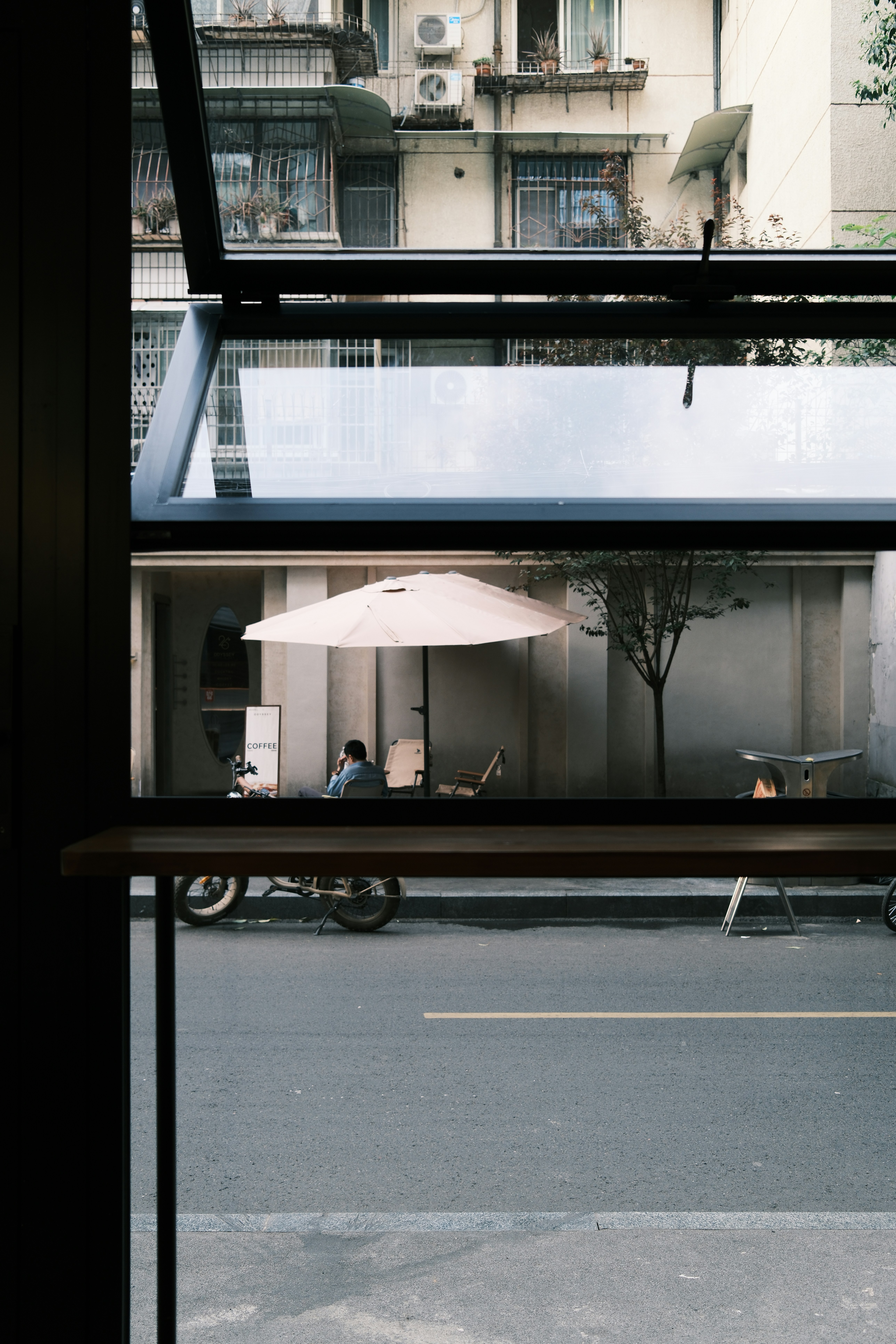 Open-air Café Reflections: A Quiet Street Scene Framed by Glass and Shade
