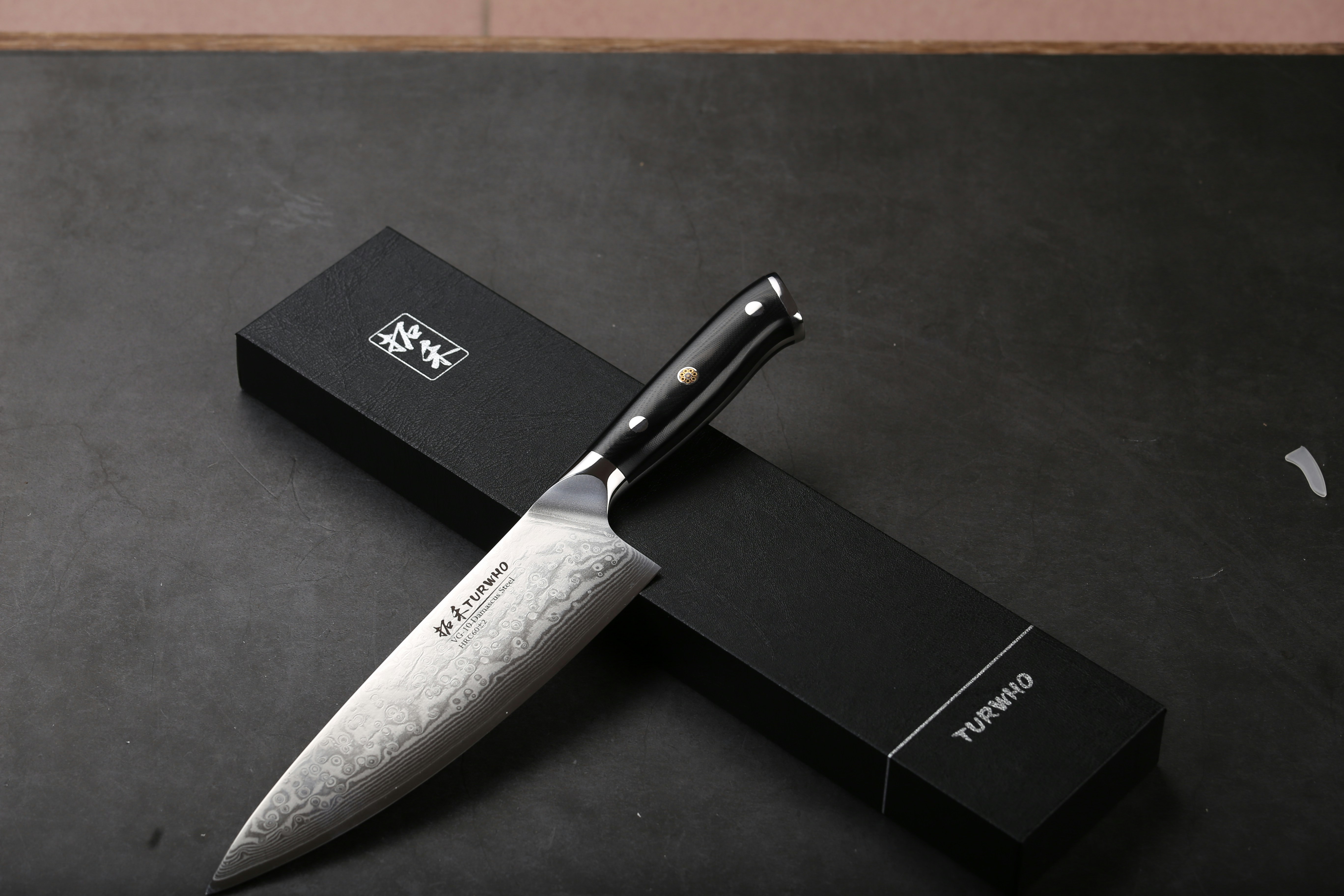 Damascus in Steel: A Damascus Chef's Knife Resting on its Box