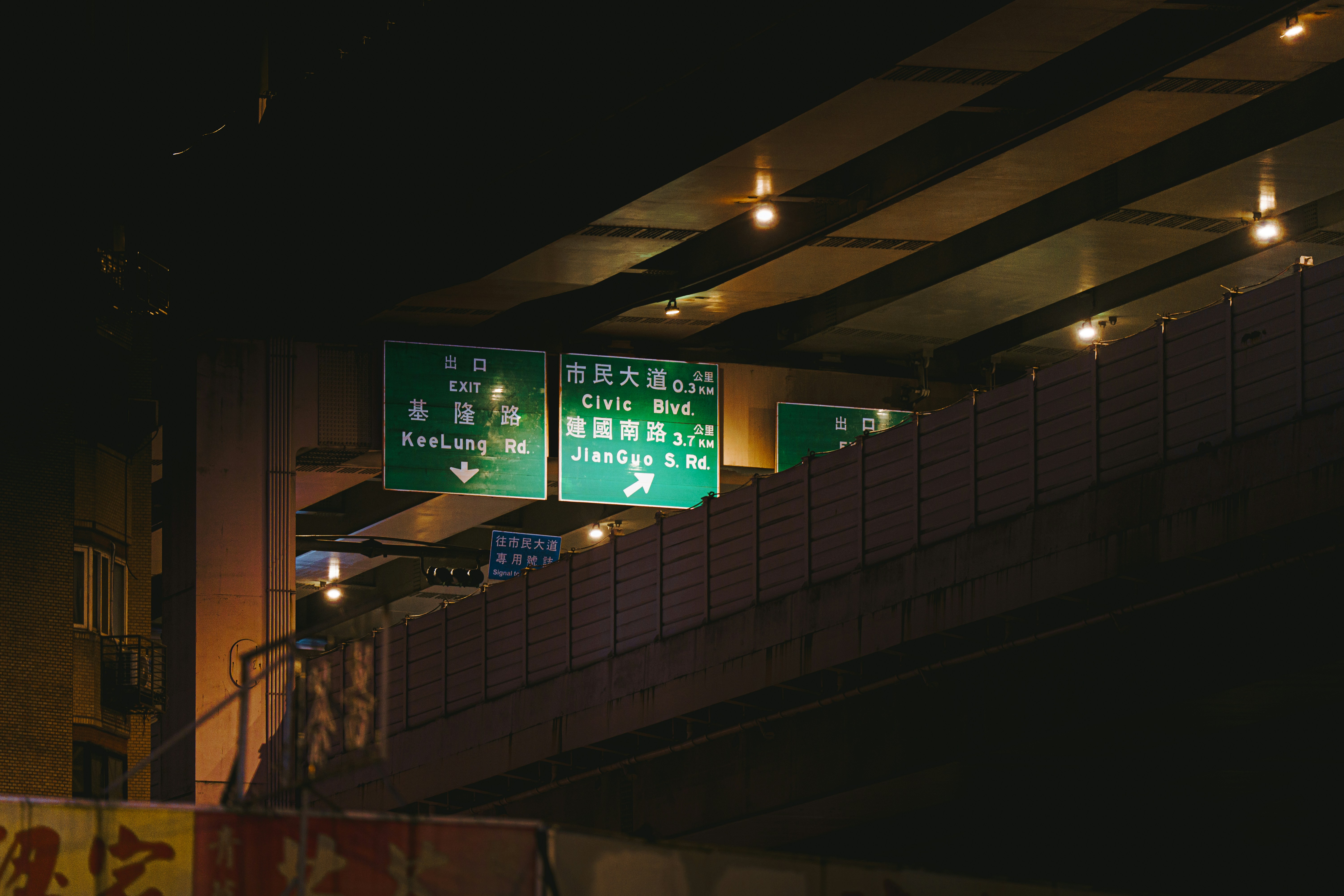 Under the Green Arches: Night Highway Signs Above a Quiet Overpass