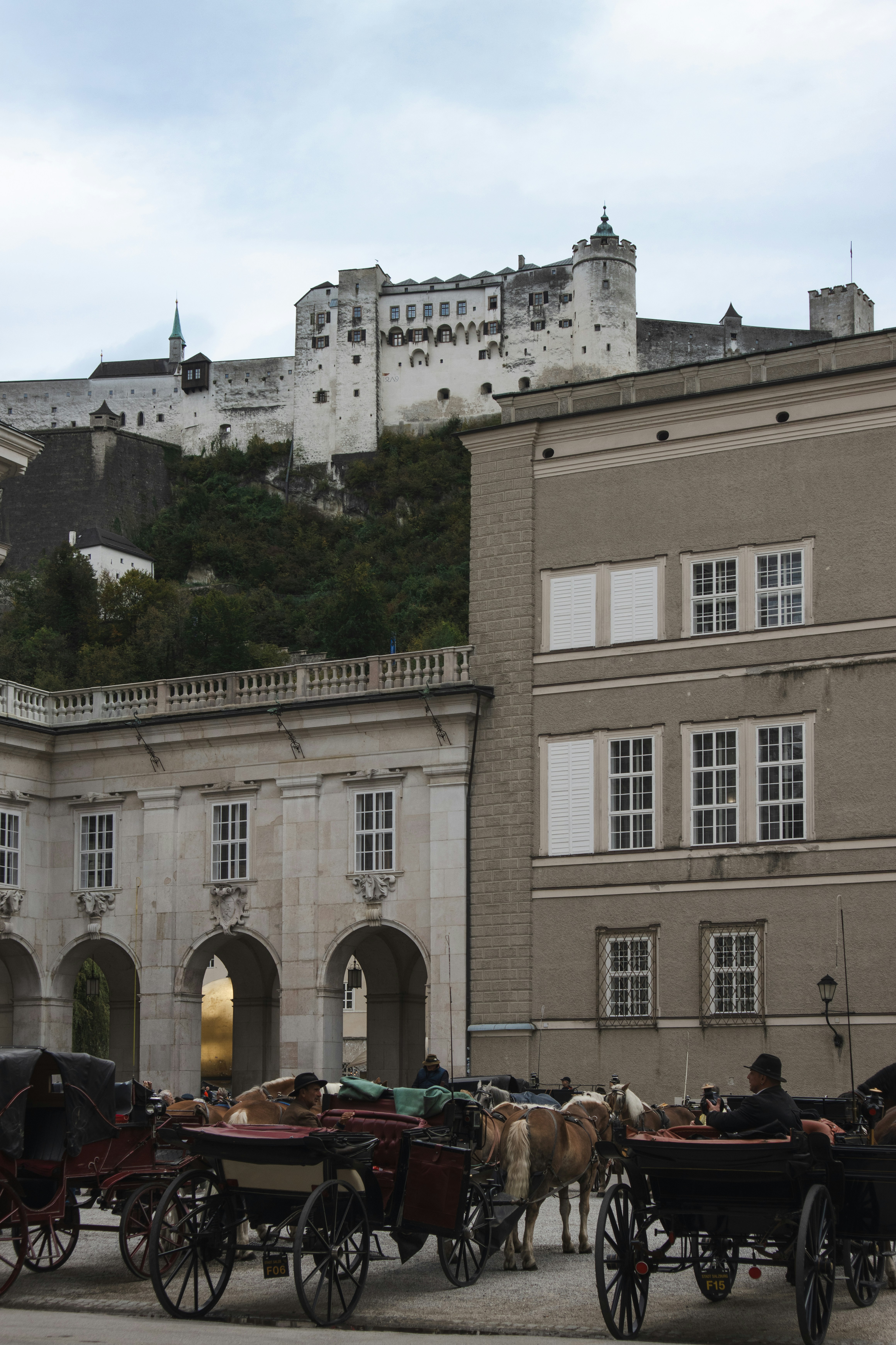 Horse-drawn Carriages in a Historic Squarescape under a Fortress Terrace