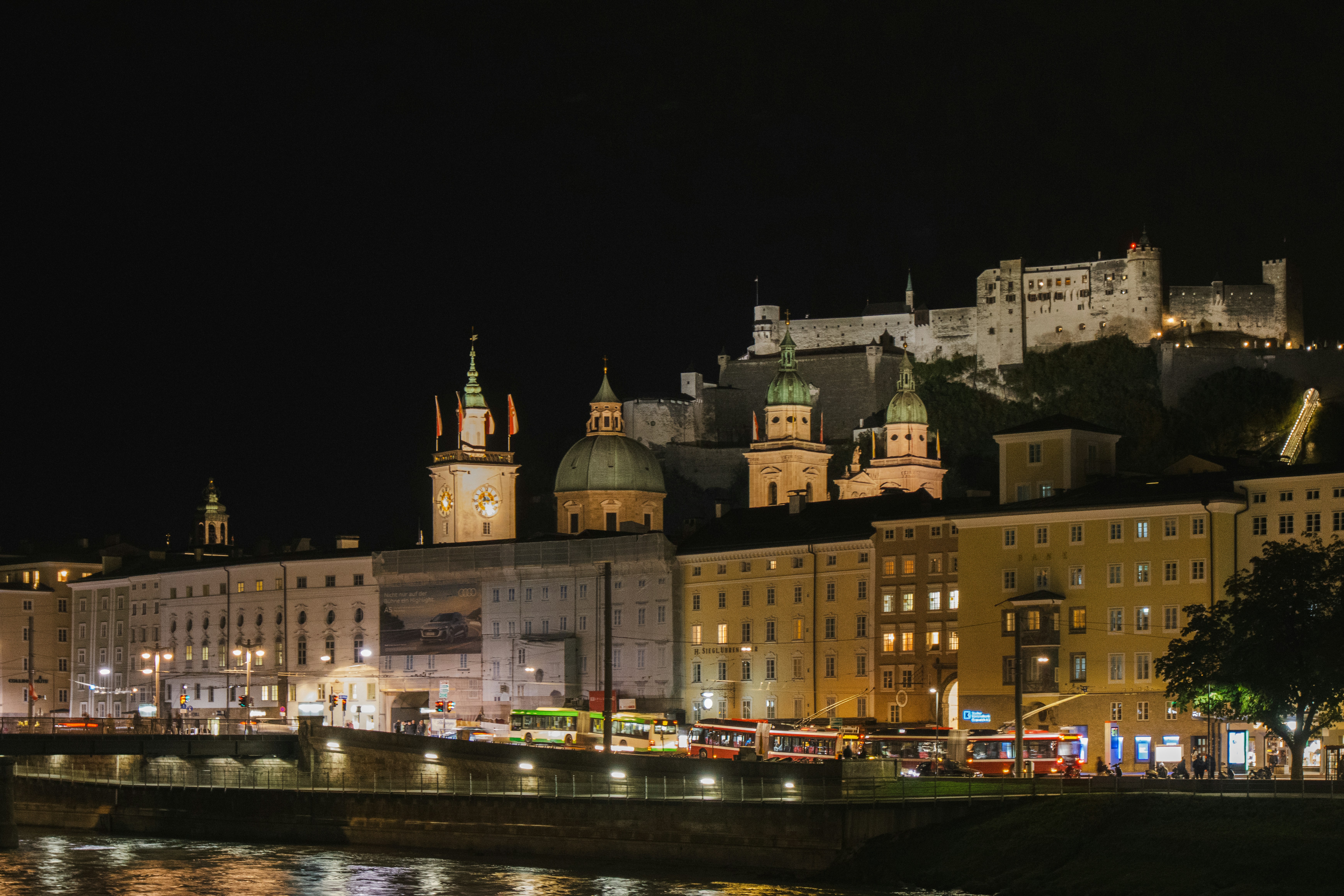 Nighttime riverside in Innsbruck: illuminated facades and fortress above