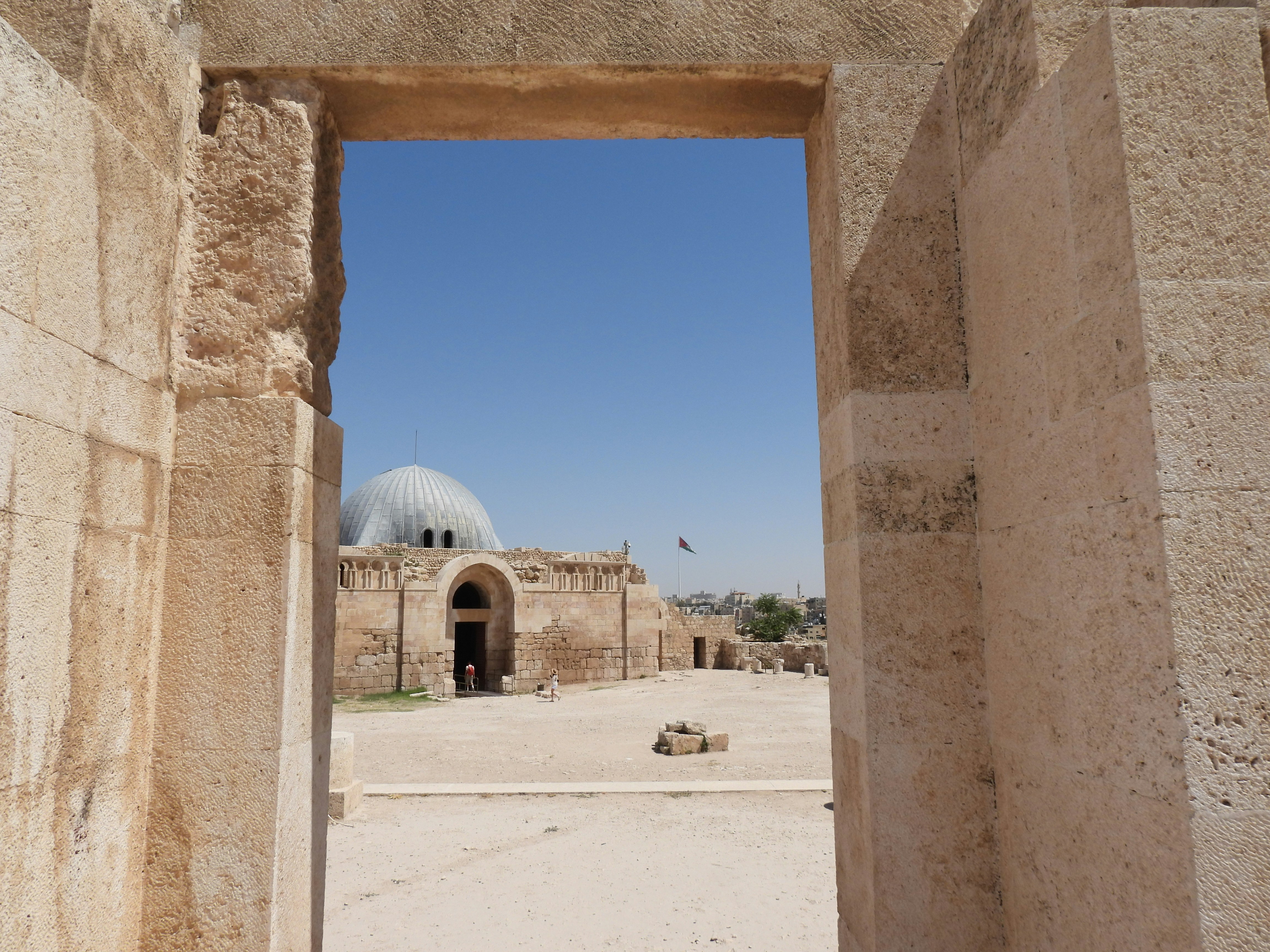 Stone doorway framing ancient ruins and a dome.