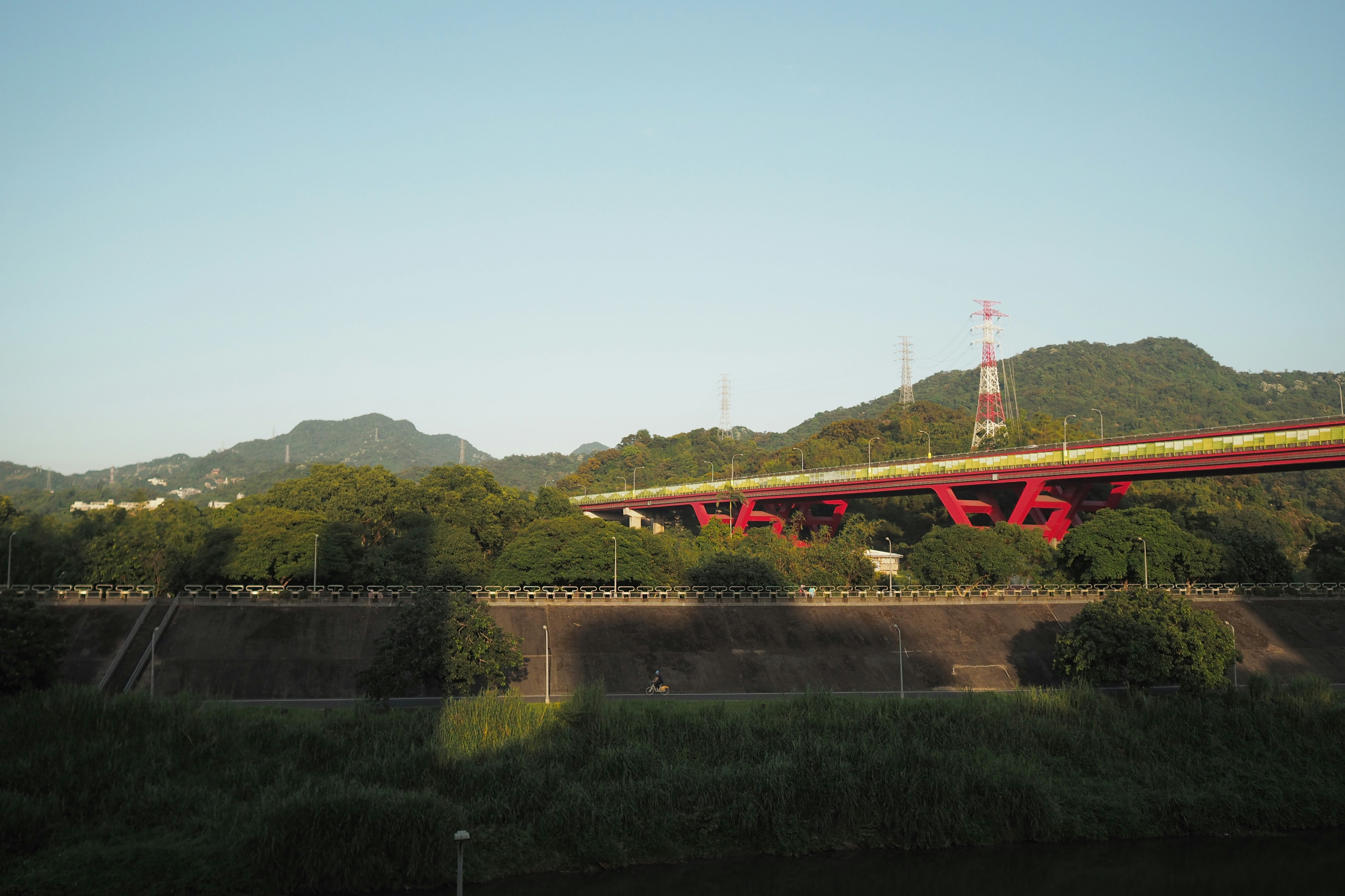 Red Bridge Over Green Hills: Sunset Silhouette of Infrastructure