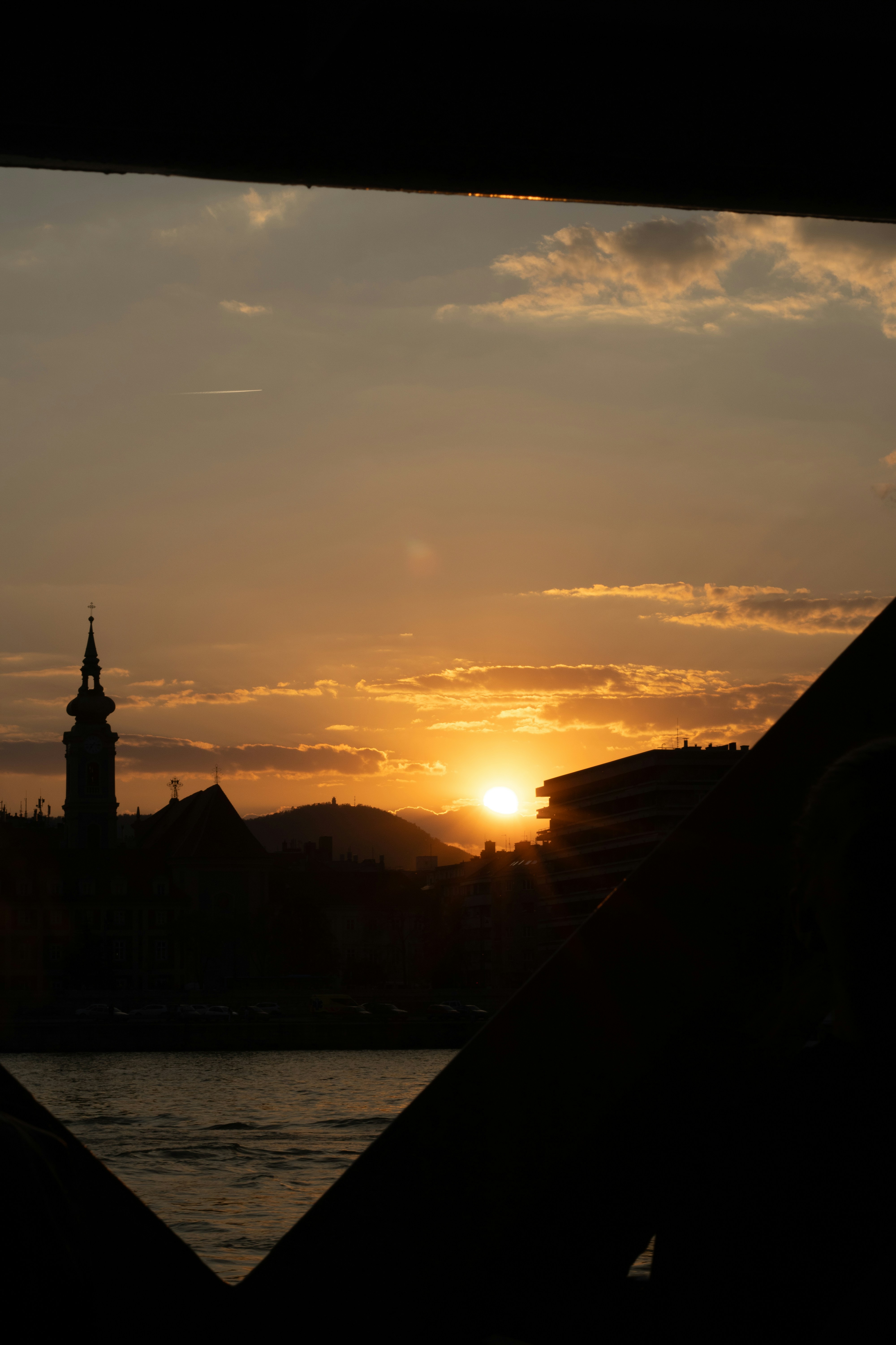 Sunset Between Dark Ribs: A Geometric City Silhouette over Water