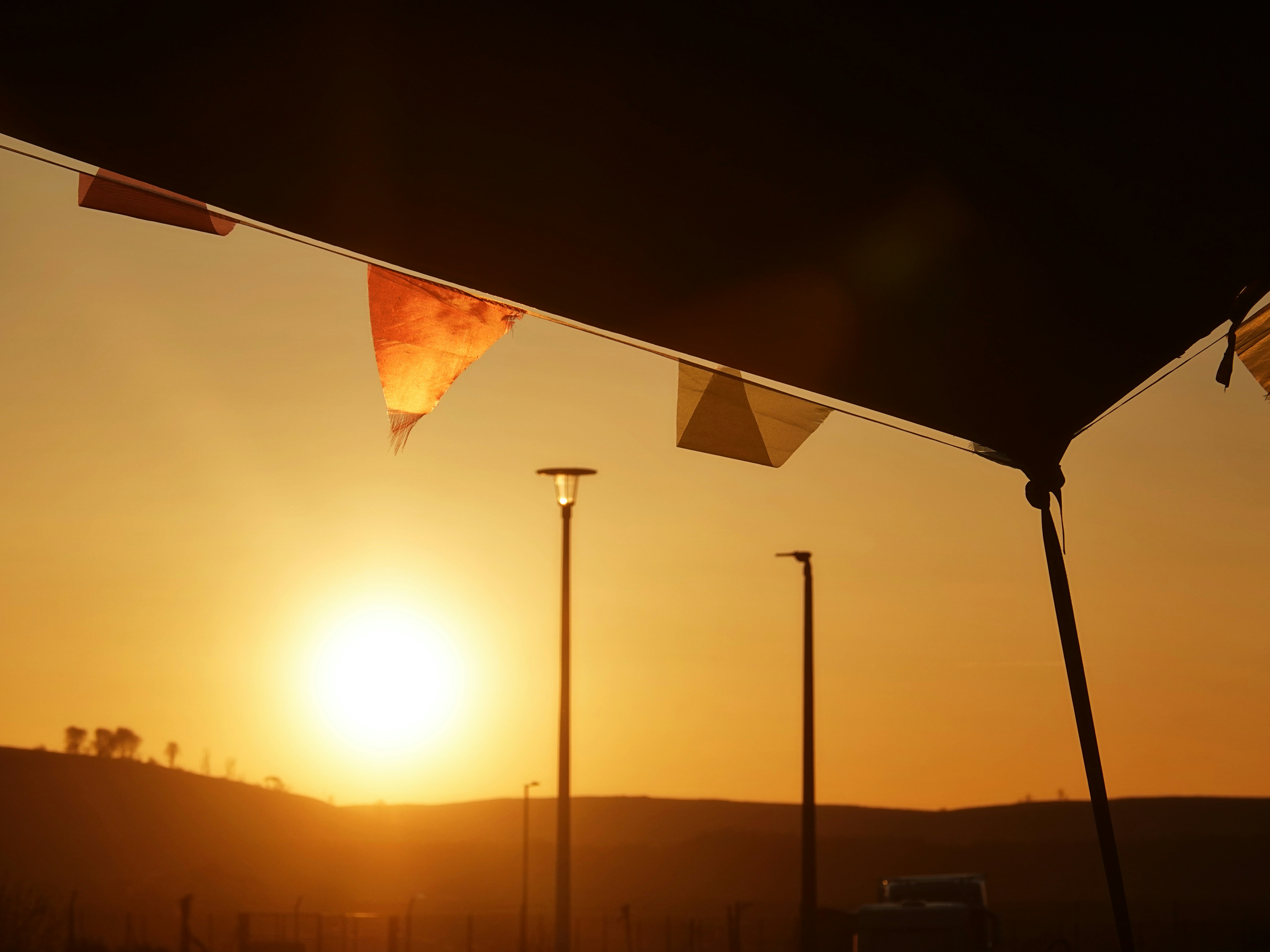 Sunlit Desert Verge: Flags, Poles, and a Quiet Horizon