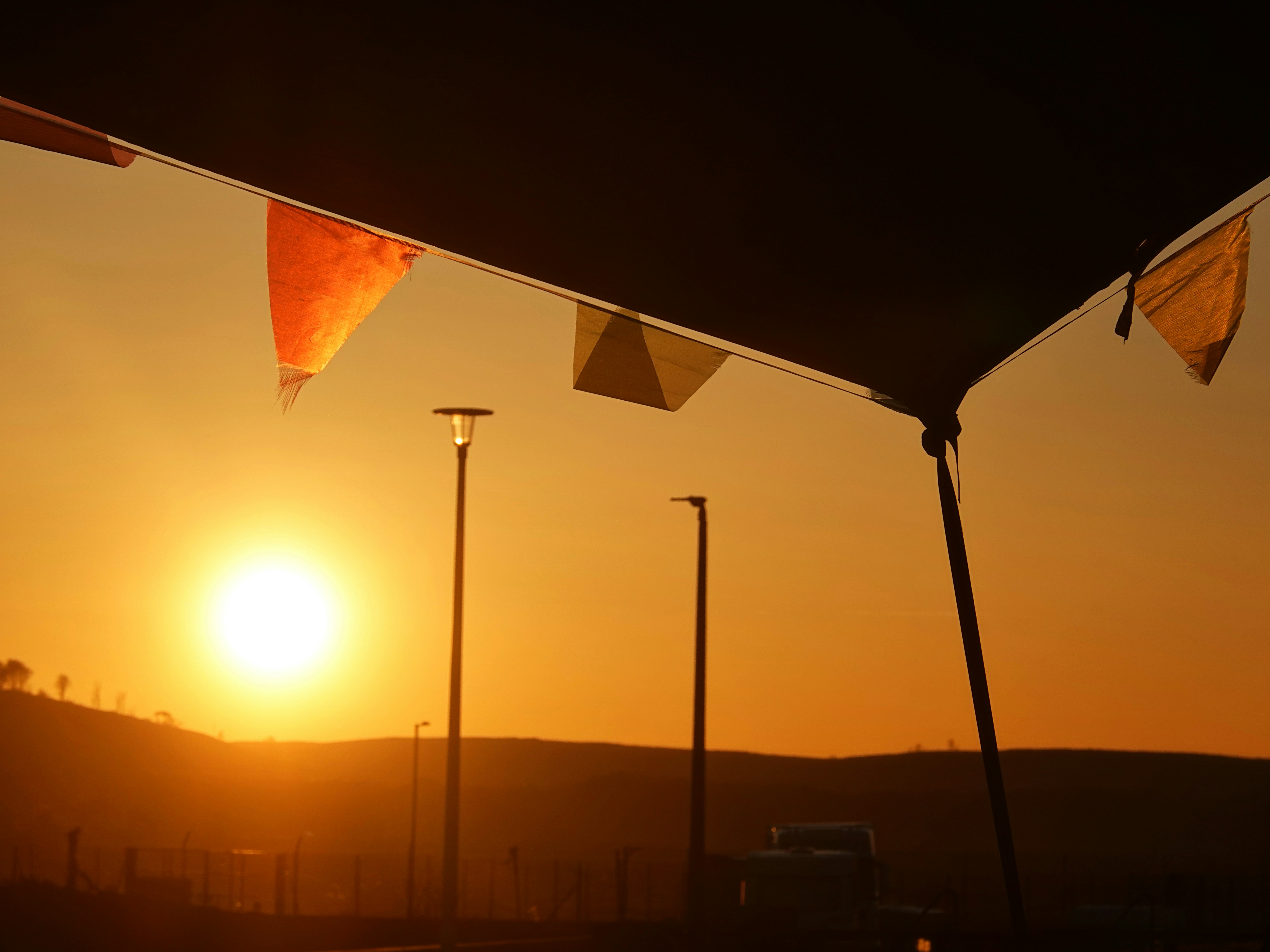 Golden Hour Under Flags: Sunset Silhouette at the Field Edge