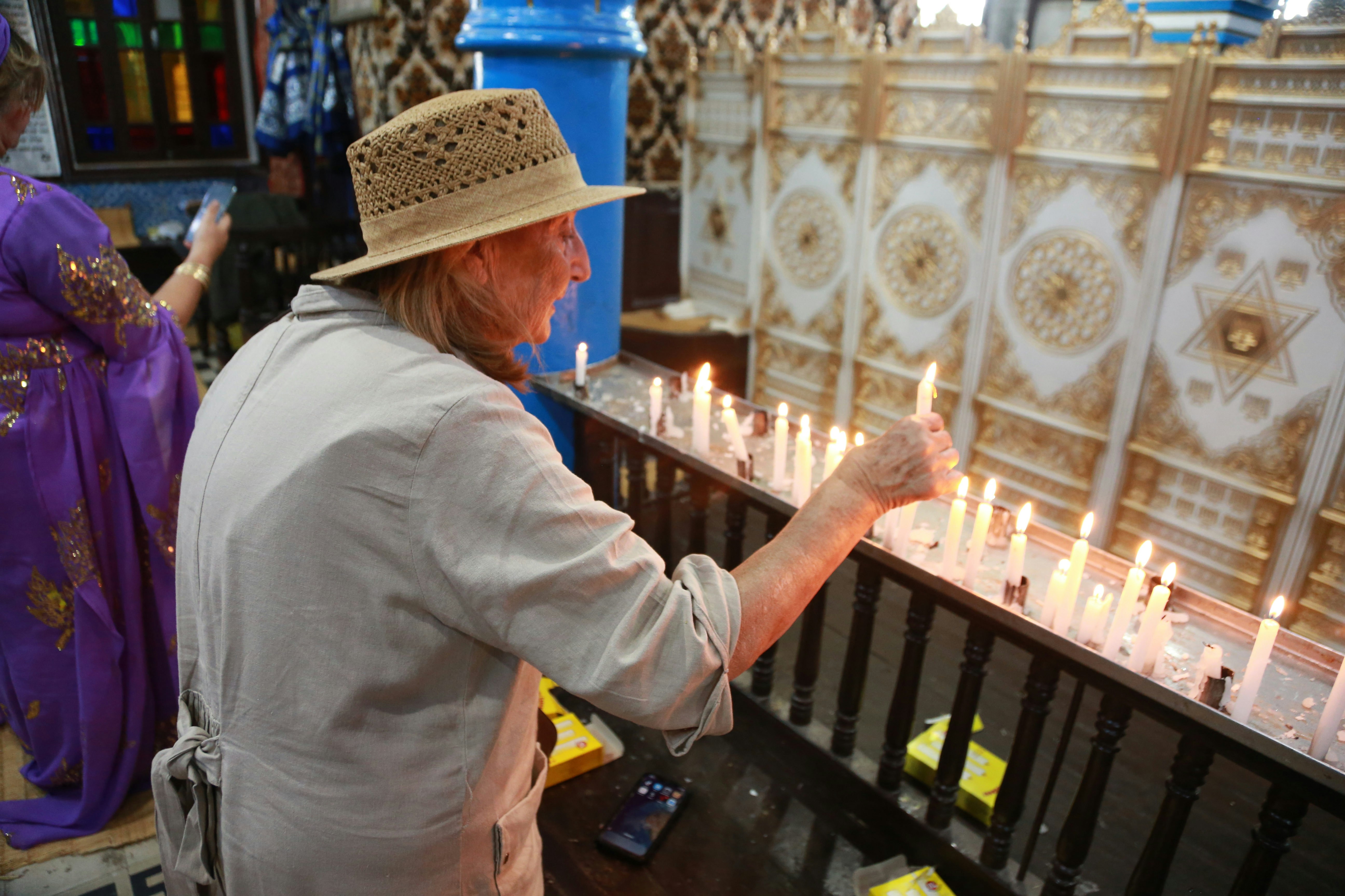 Candles, Hat, and Hands: A Quiet Moment at the Shrine