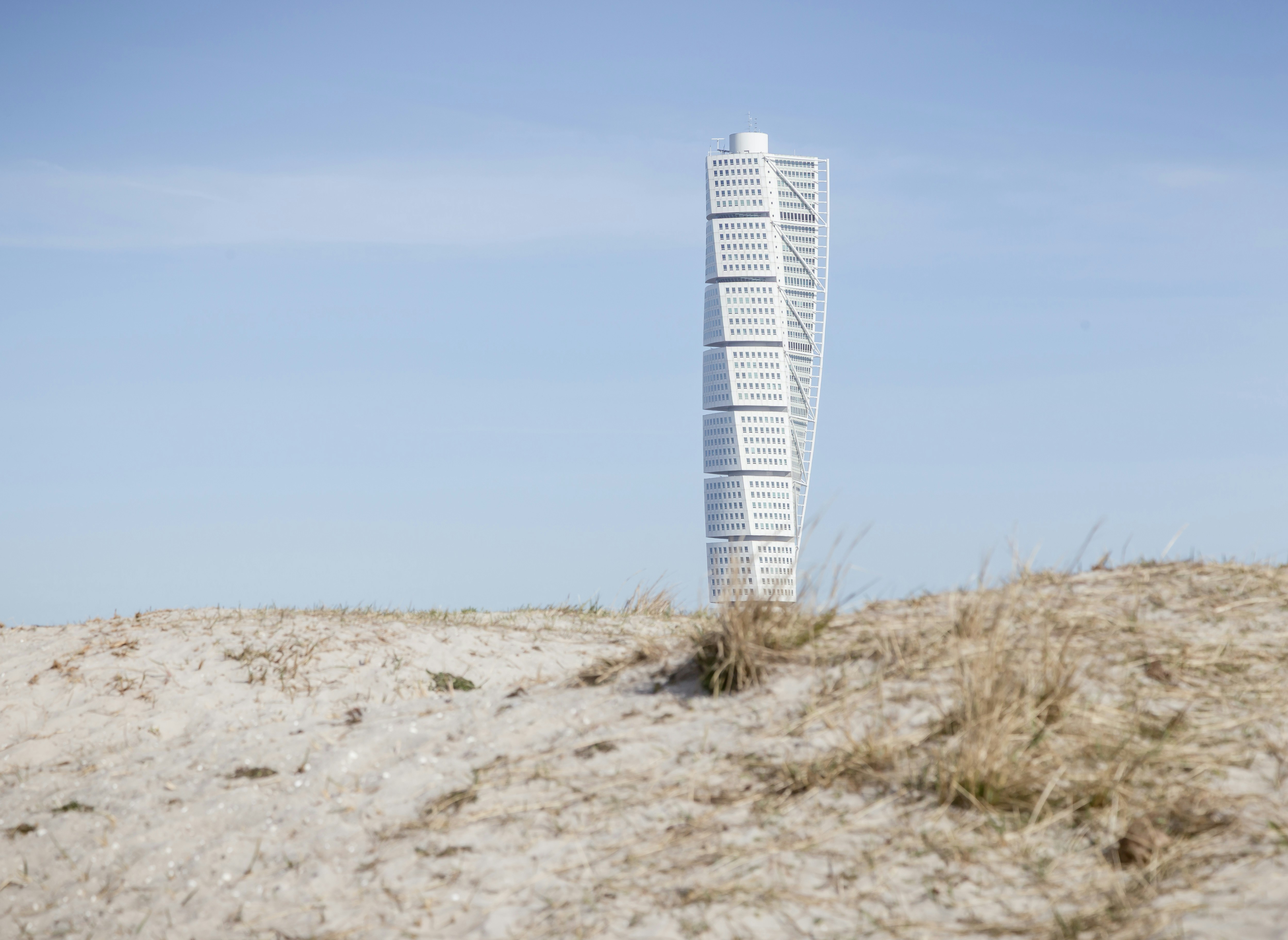 White spiral tower rising from wind-swept dunes