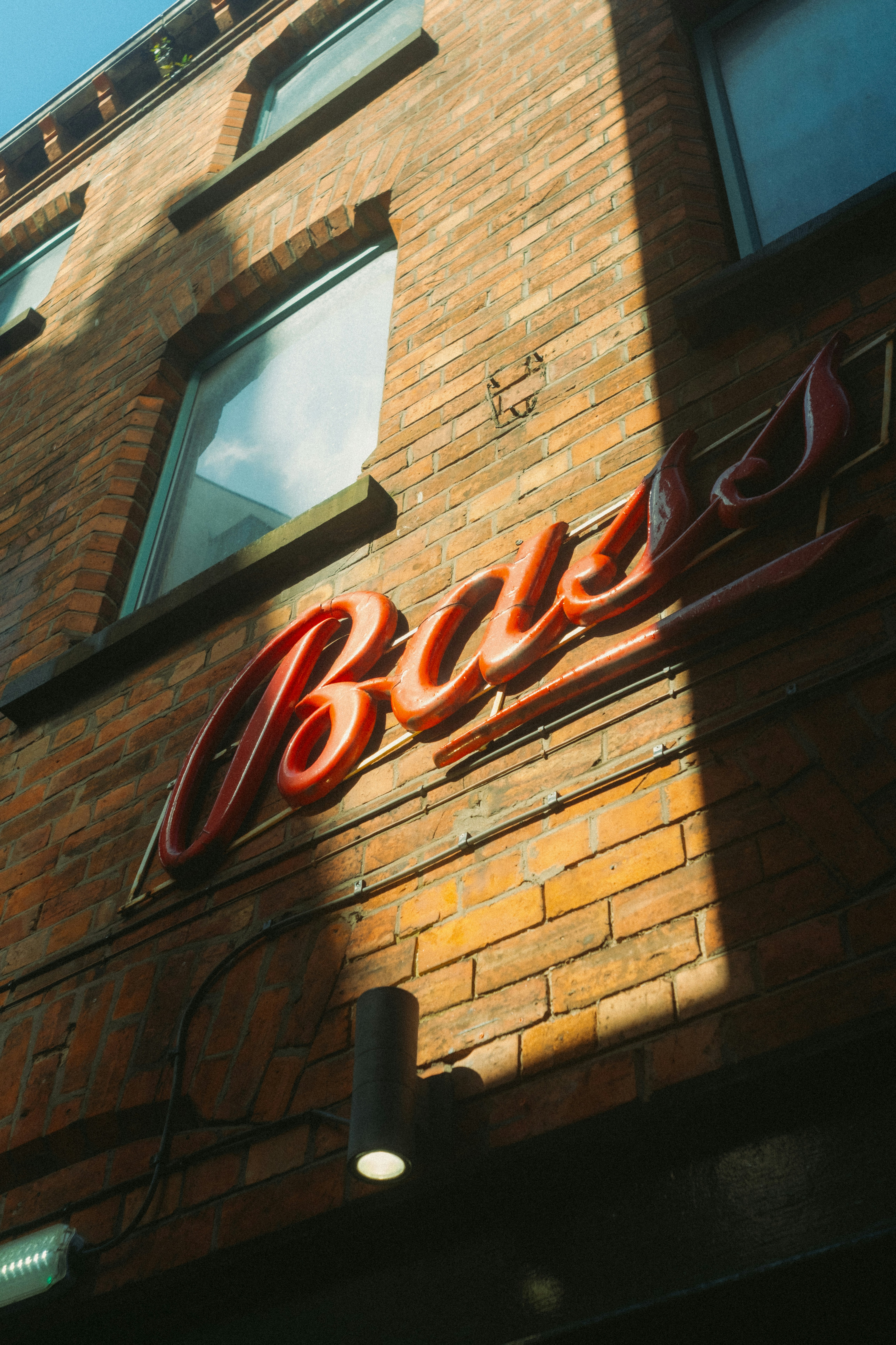 Neon Script on Brick: A Street-Side Façade Under Warm Light