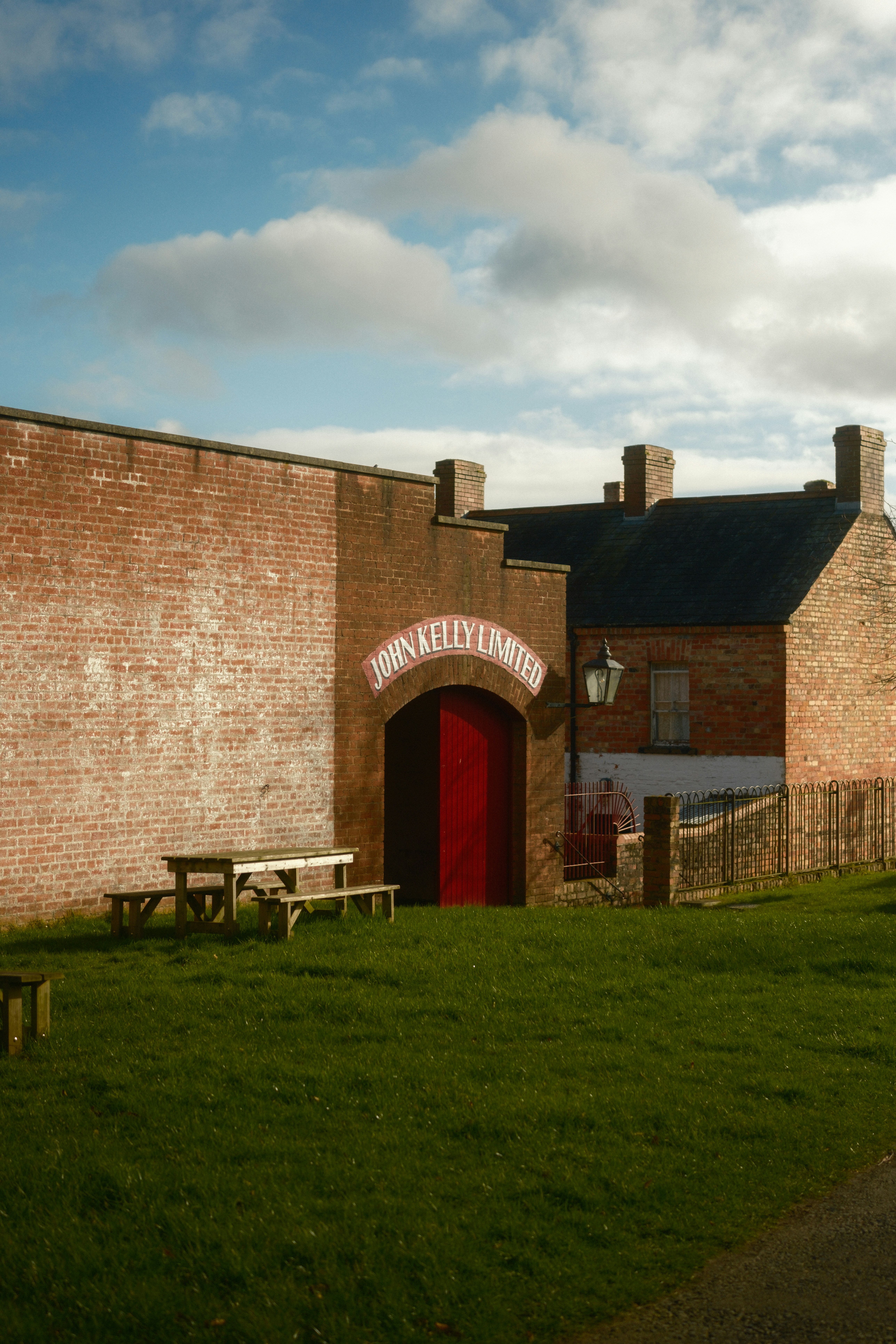 Red Bricked Archway: John Kelly Limited Entryway in Sunlit Yard
