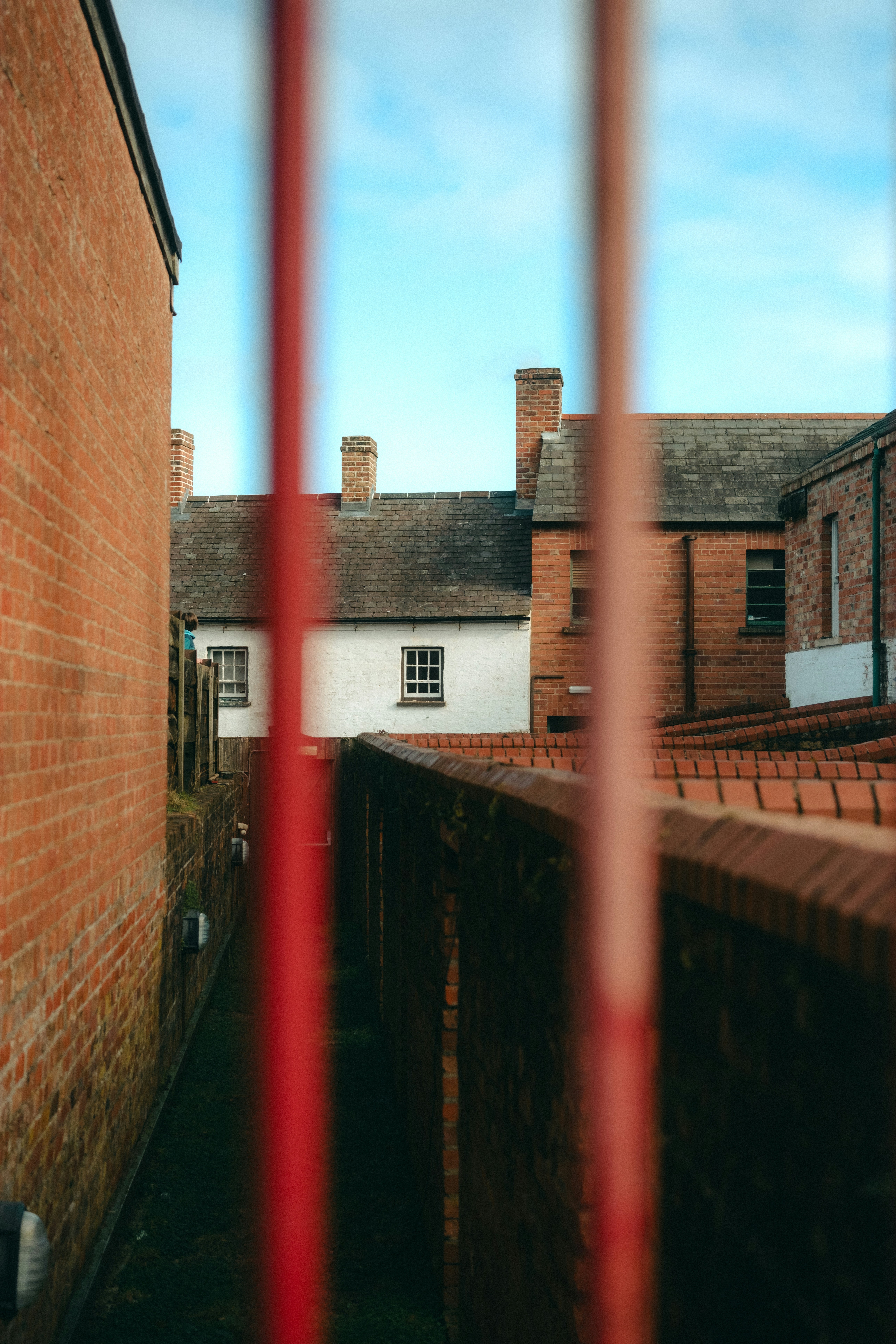 Through the Rails: A Narrow Urban Corridor Framed by Red Bars