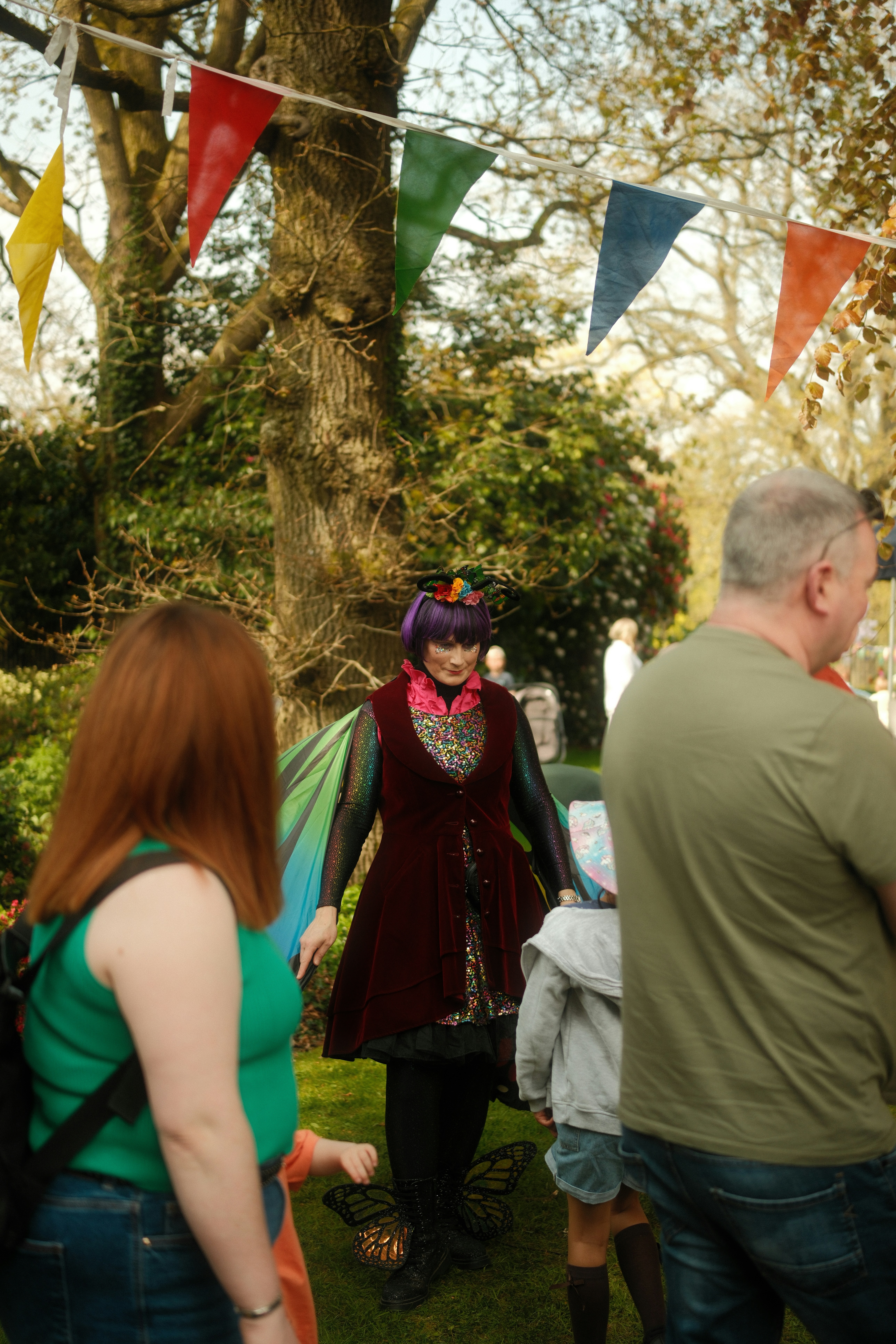 Costumed Character Beneath Colorful Flags at a Garden Festival