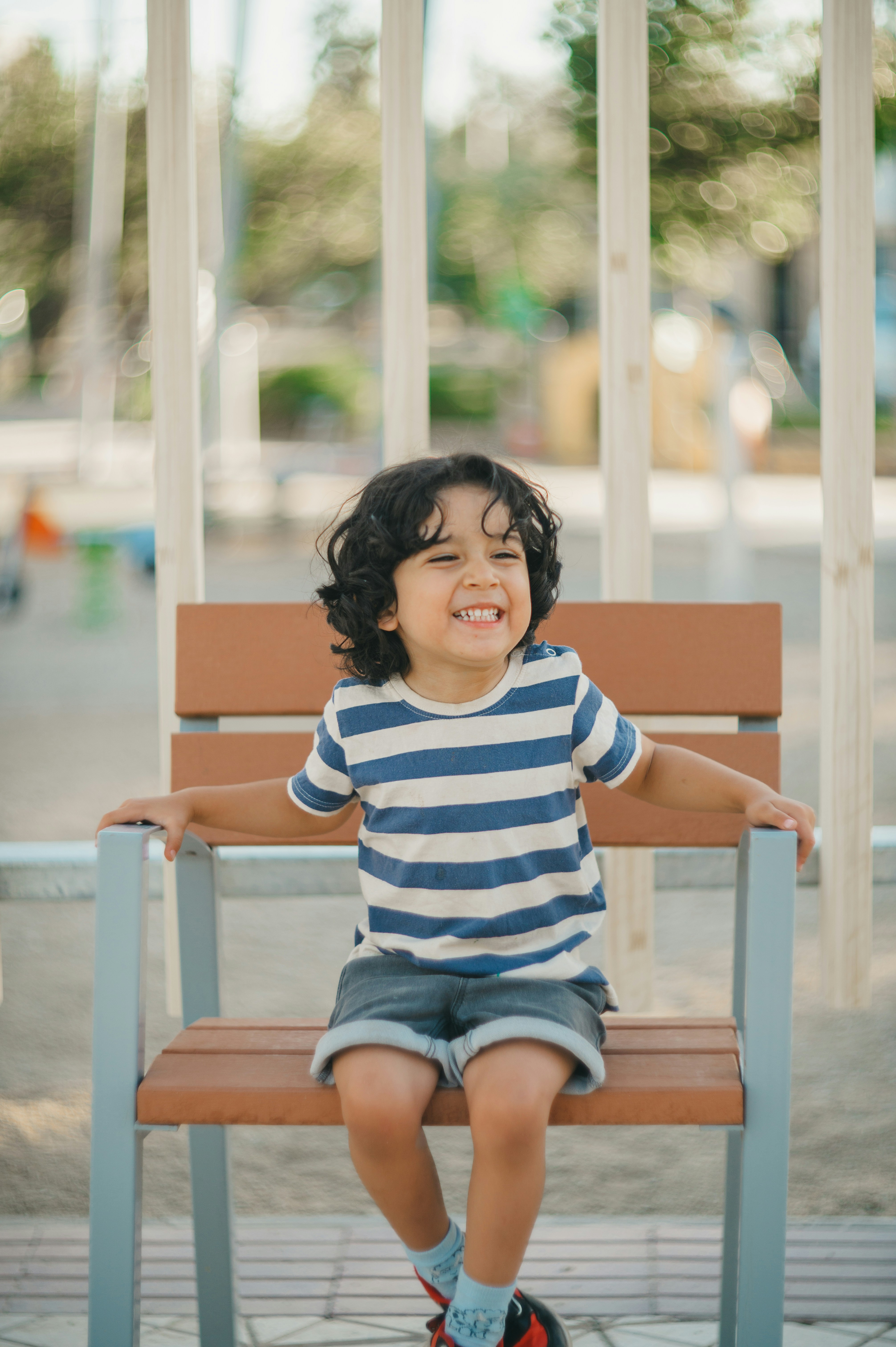 Smiling Child on a Park Bench Laughs Amid Vertical Bars