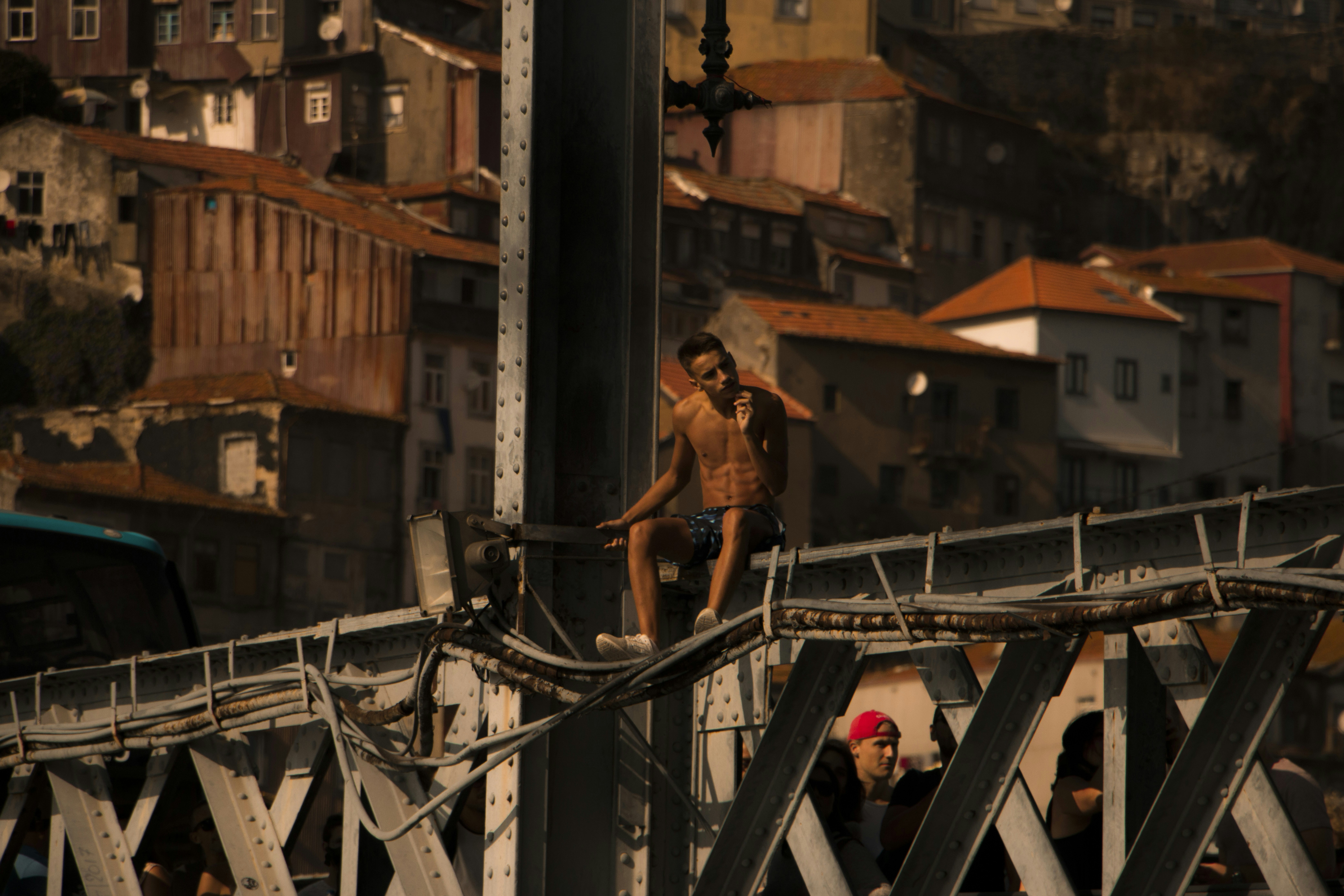 Barefoot climber on a weathered bridge against a hillside village