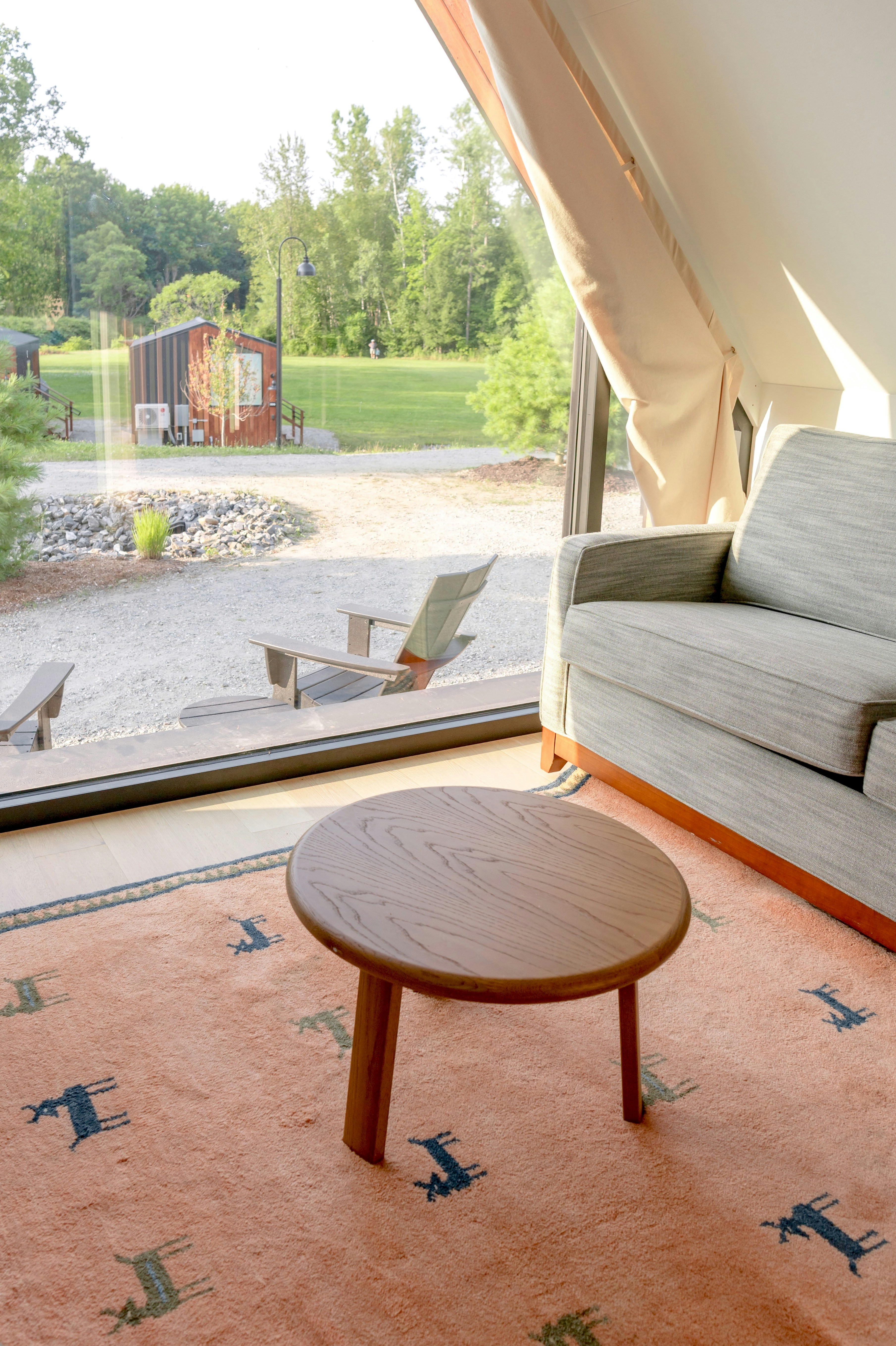 Sunlit living room with panoramic window framing a serene outdoor scene