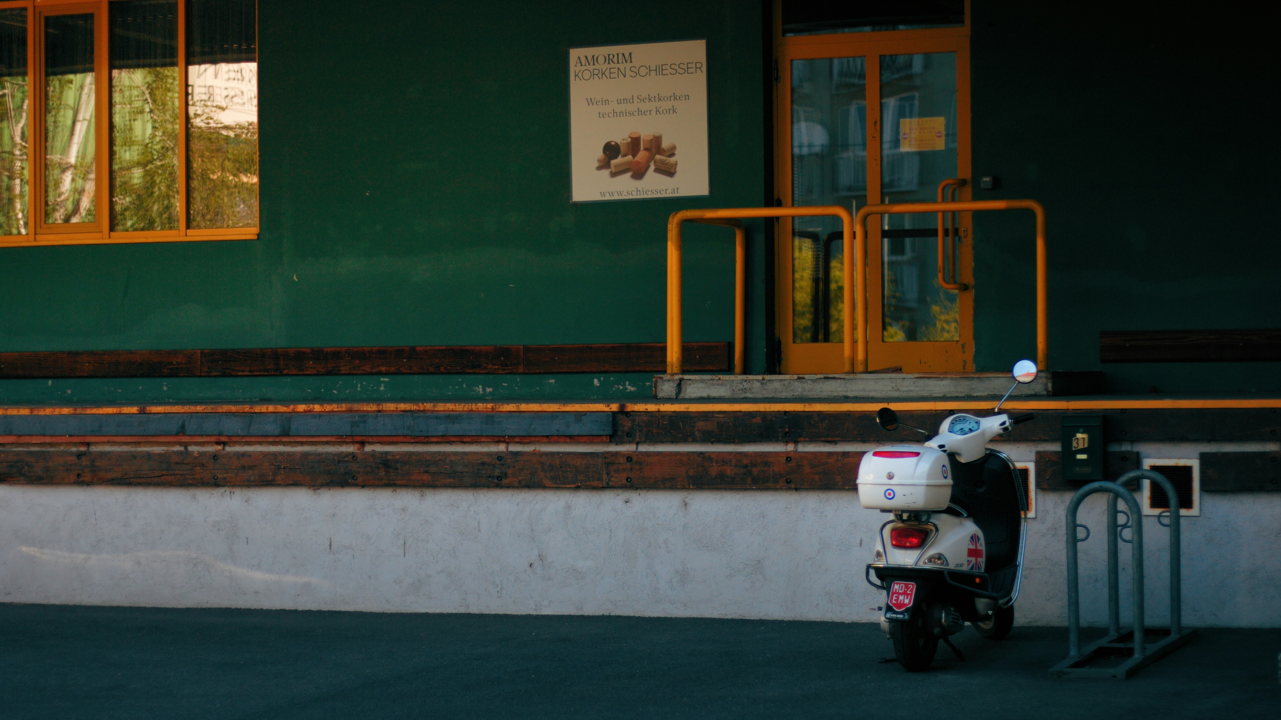 Quiet Corner: A Vespa Resting by a Sunlit Green Wall