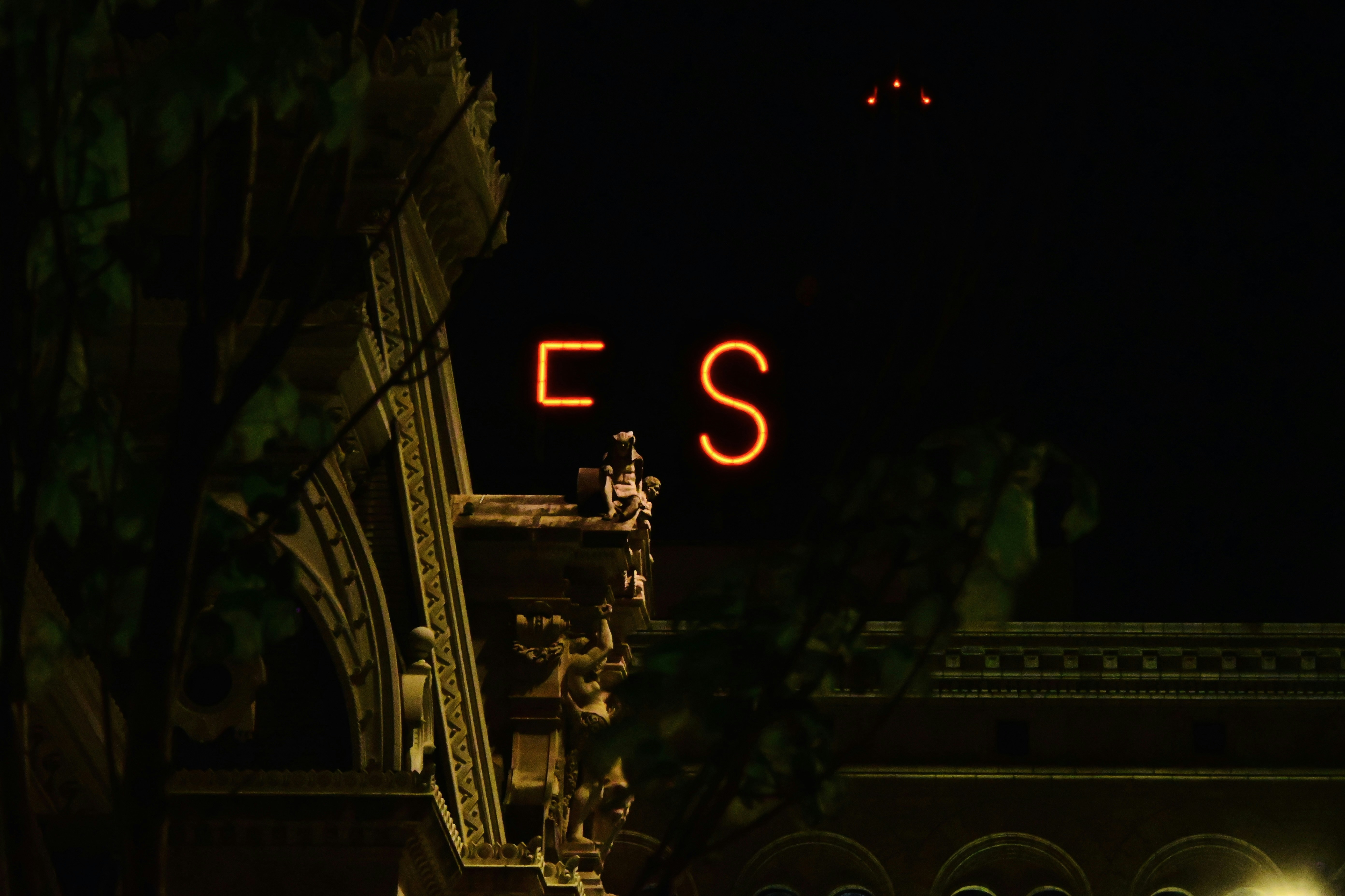 Neon Sign Above Historic Facade at Night