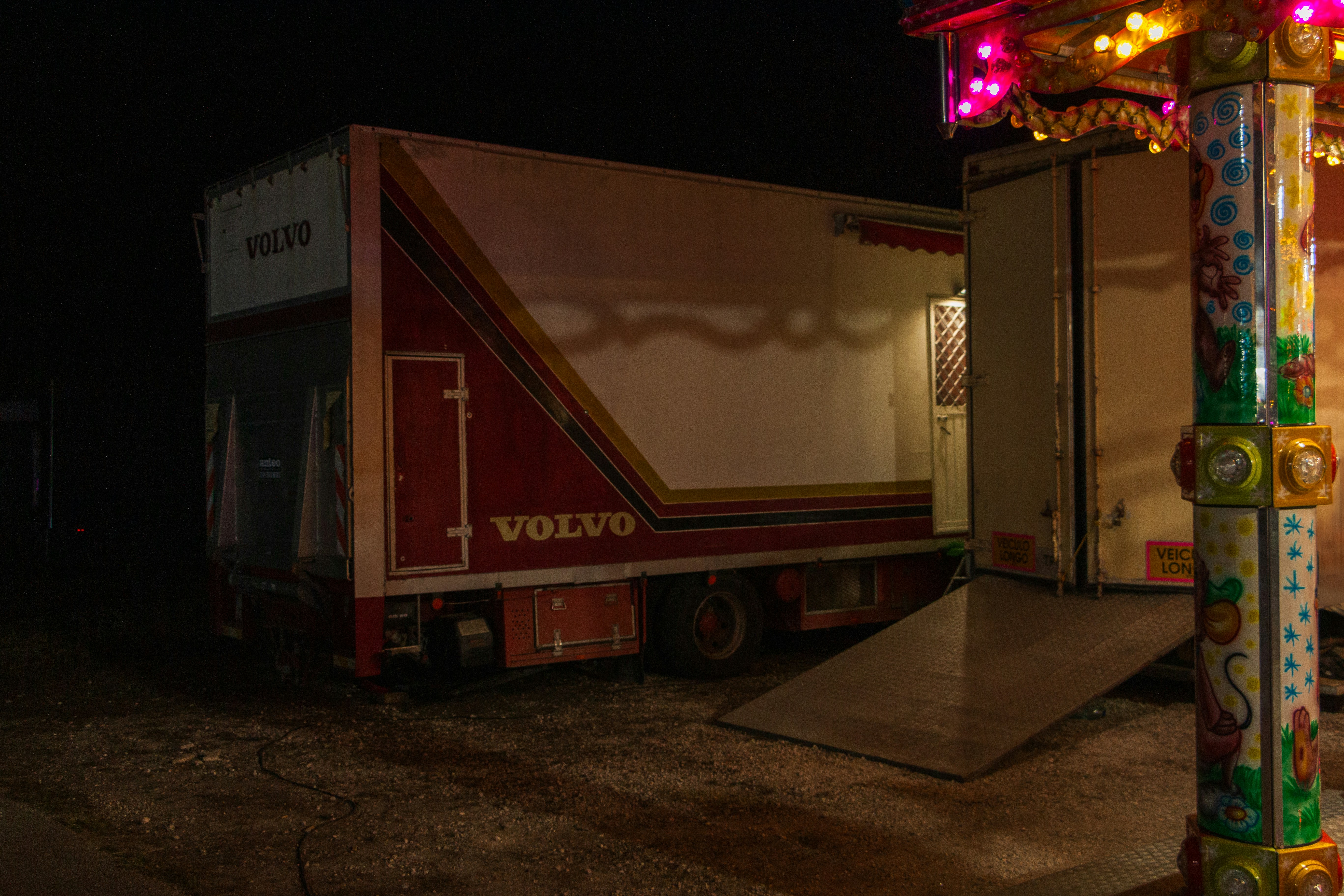 Dim fairground trailer at night with illuminated carousel column