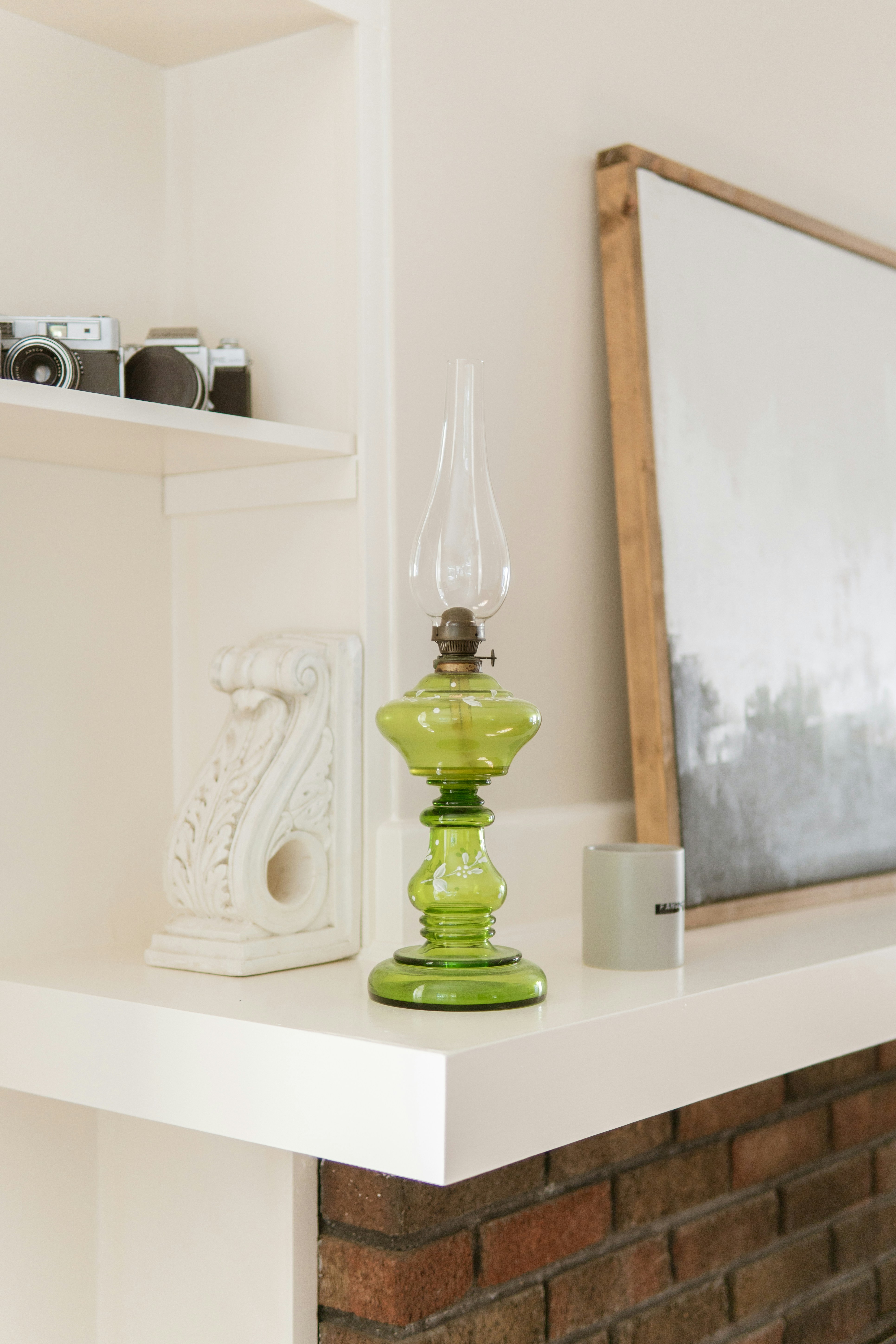 Green Glass Lamp on a Minimal White Mantel Amid Vintage Odds-and-Ends