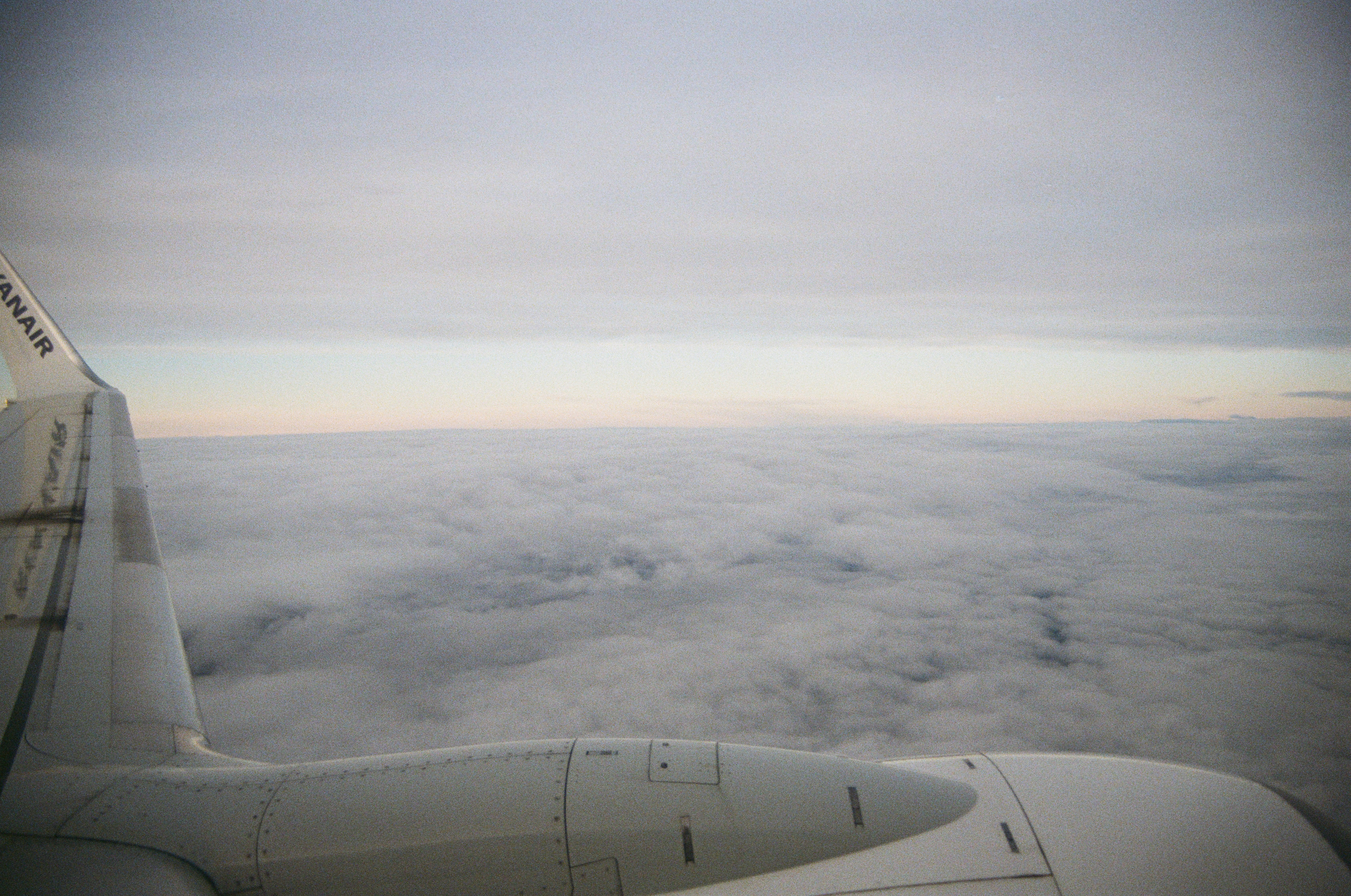 A Quiet Sky Fold: Wing and Clouds Beneath a Dawn-Born Horizon